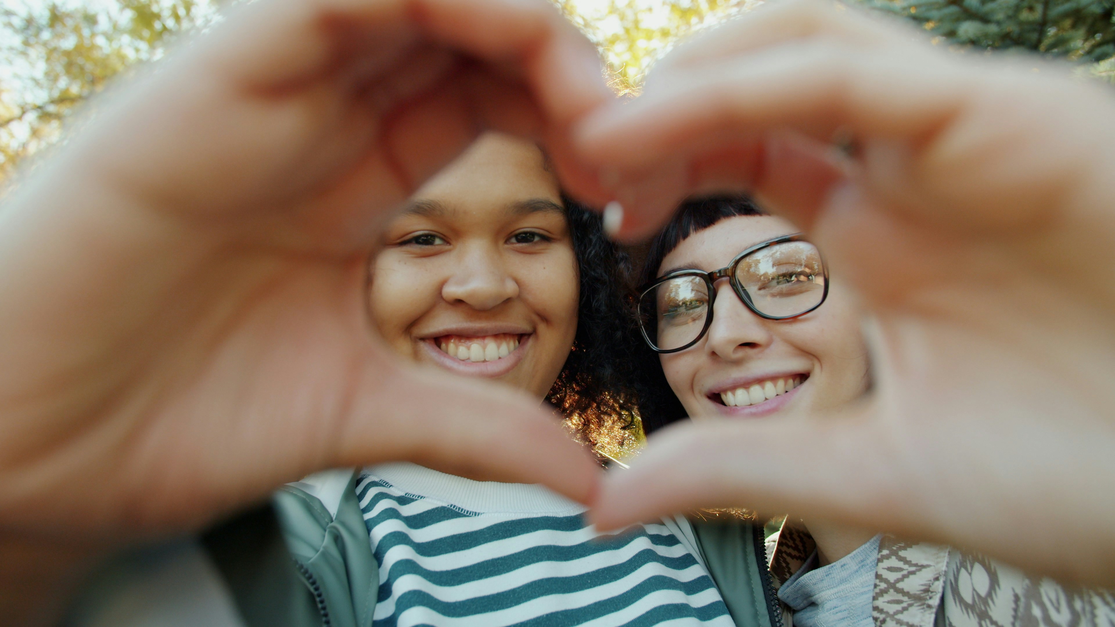 Two smiling friends make a heart shape with hands. photo – Free ...