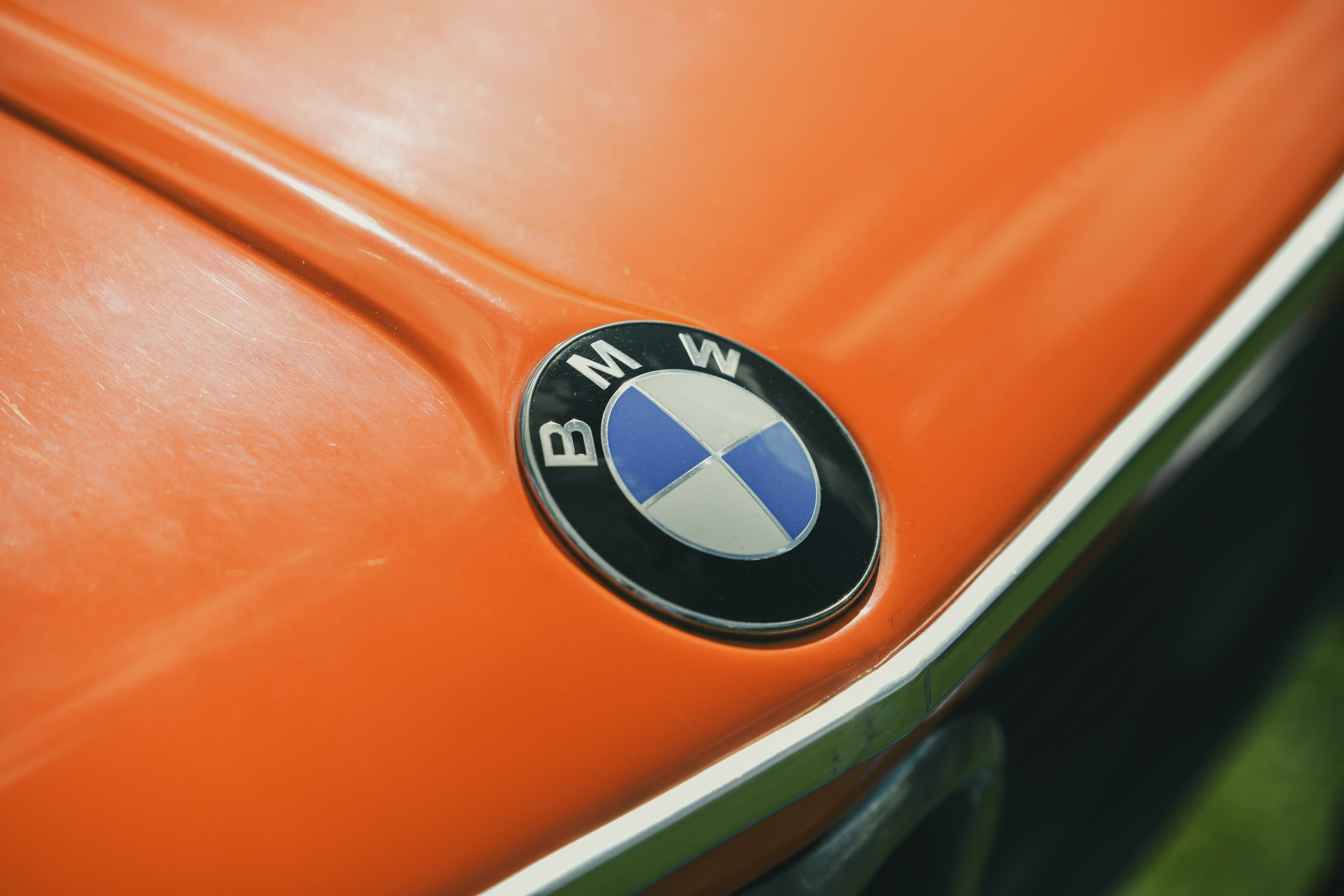 Sunlit BMW Emblem on a Vintage Orange Hood