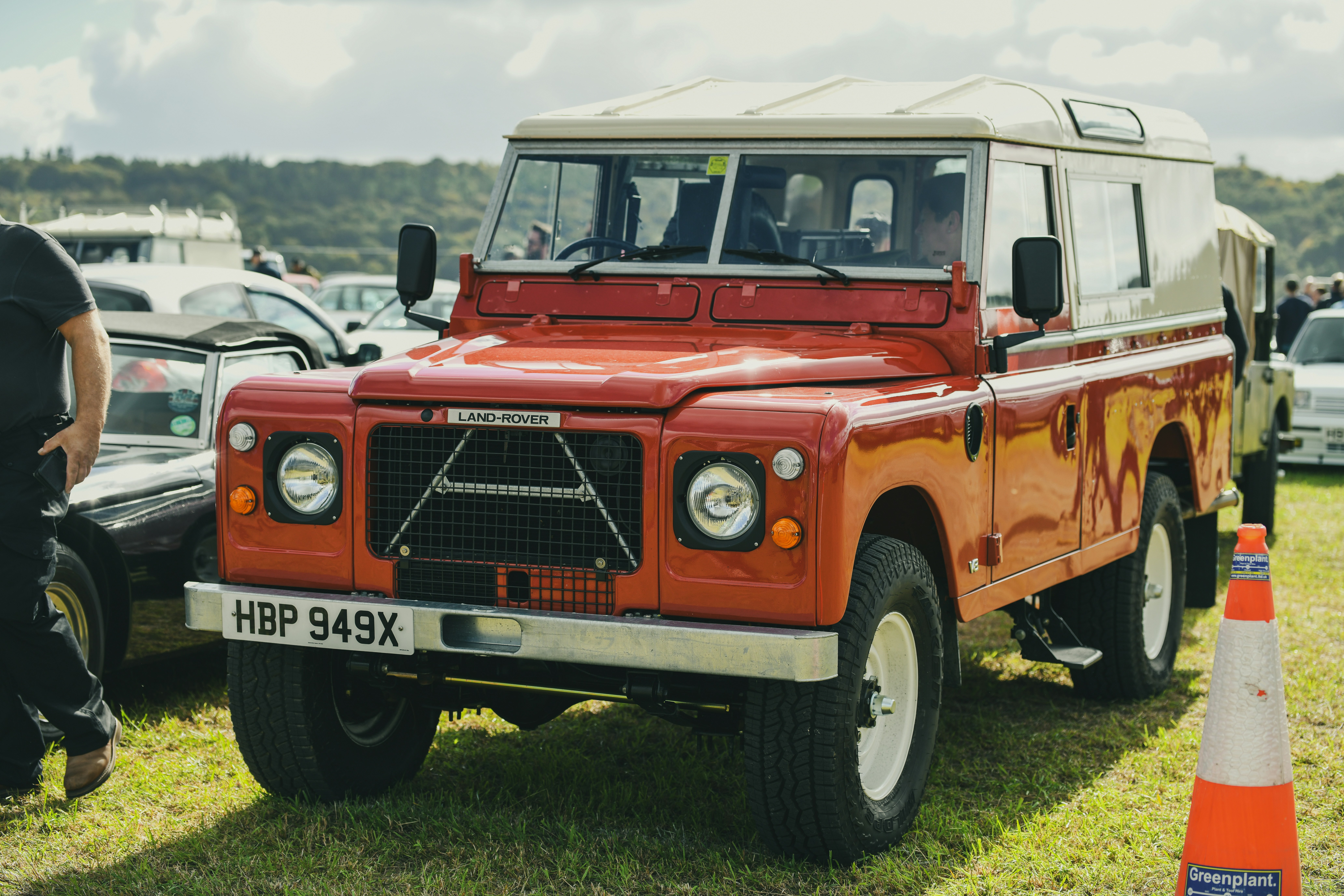 Crimson Defender at a Sunlit Car Meet: Classic Lines in a Grassy Field