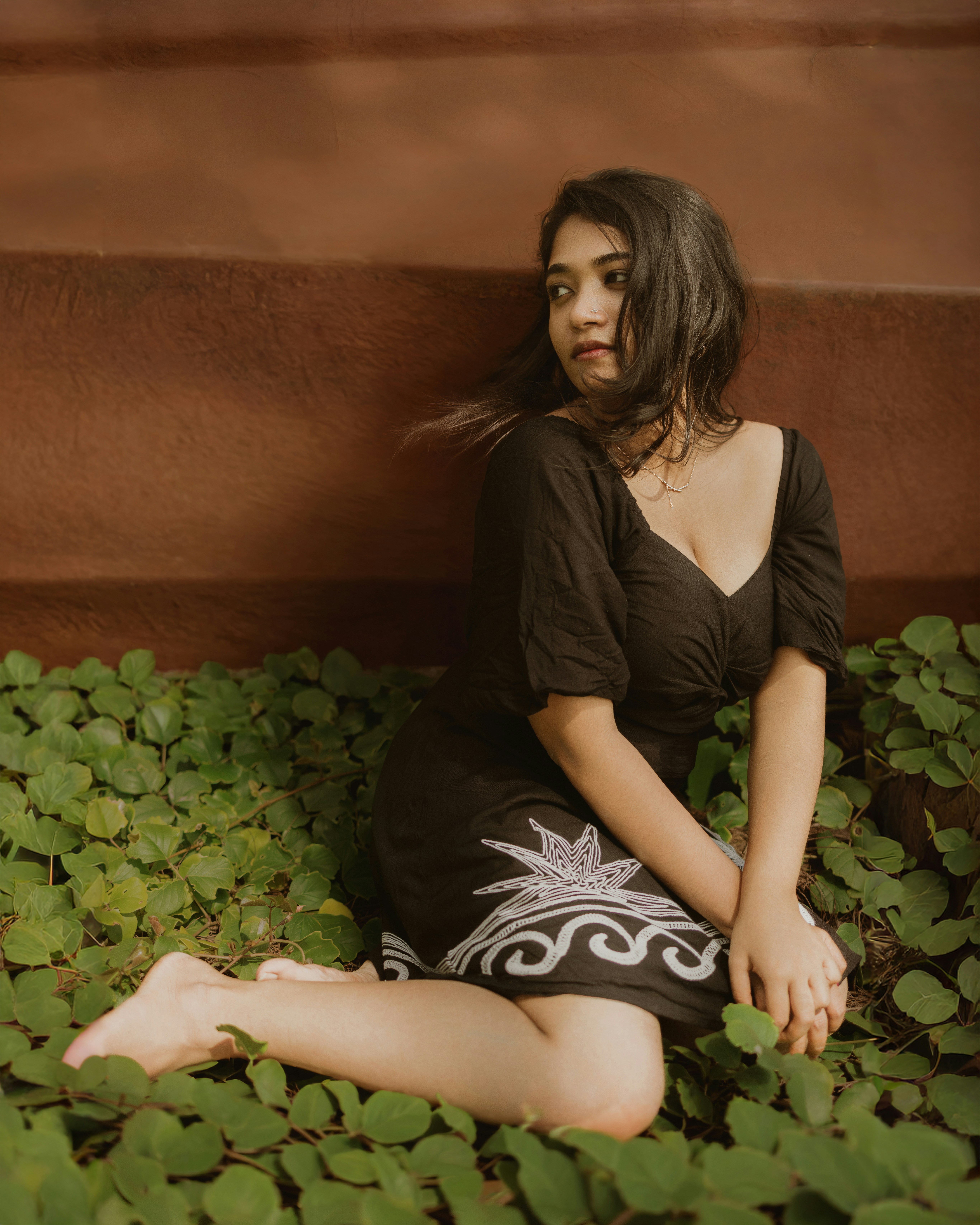 Woman in black dress sitting amongst green plants