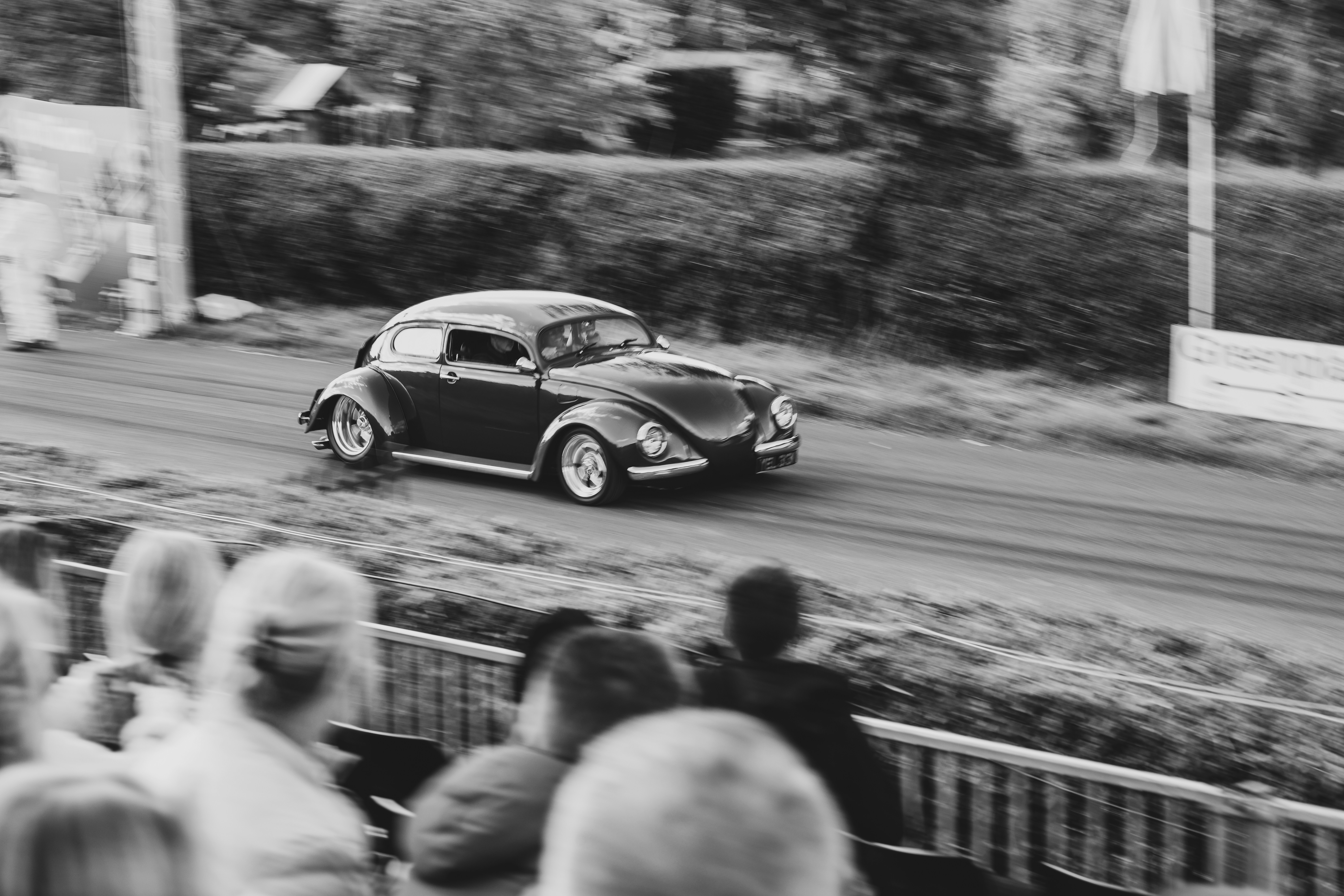 Chrome in the Slipstream: A Vintage Coupe Surges Past a Blurred Crowd