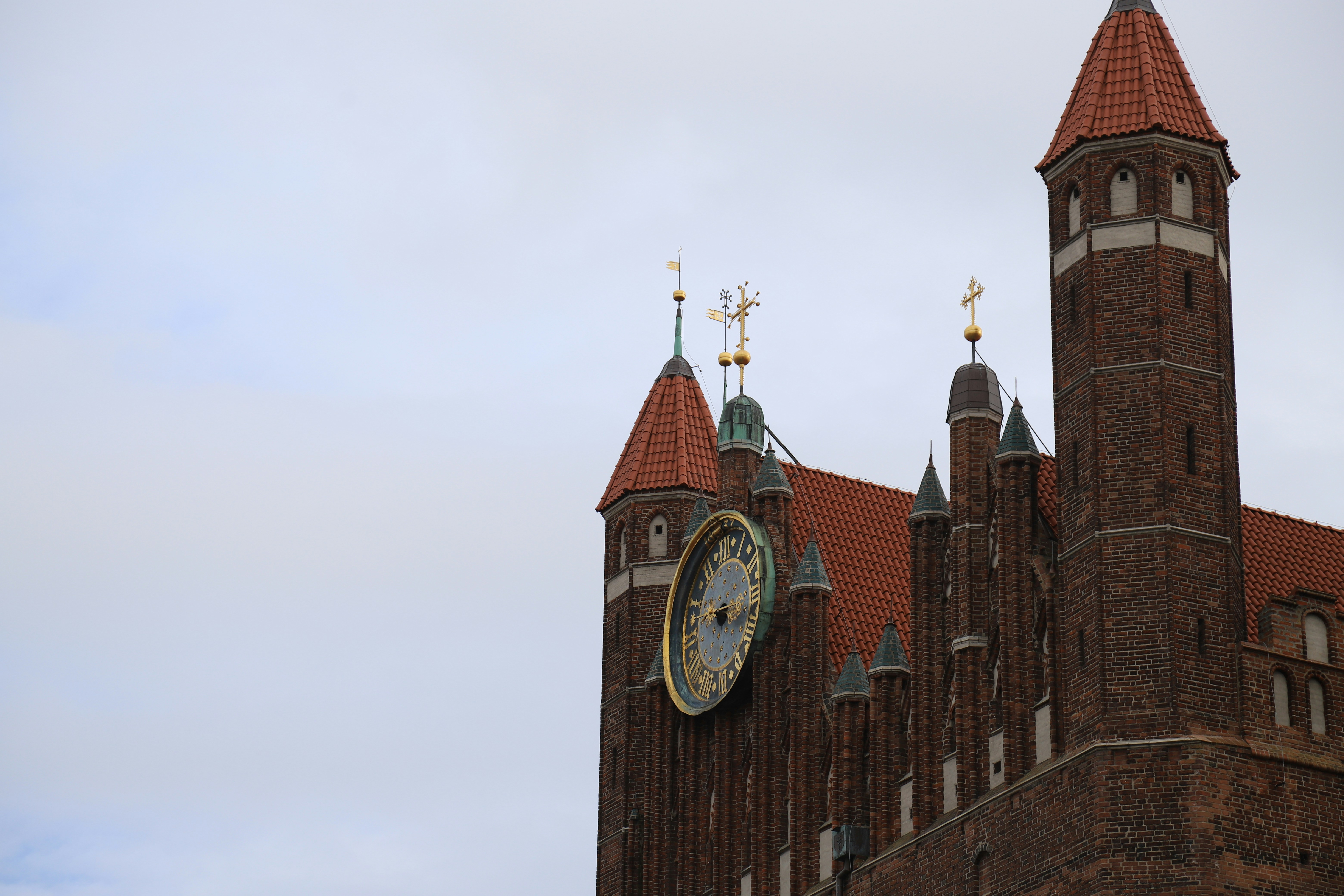 Clockface Crowned by Gothic Brickwork Under a Pale Sky