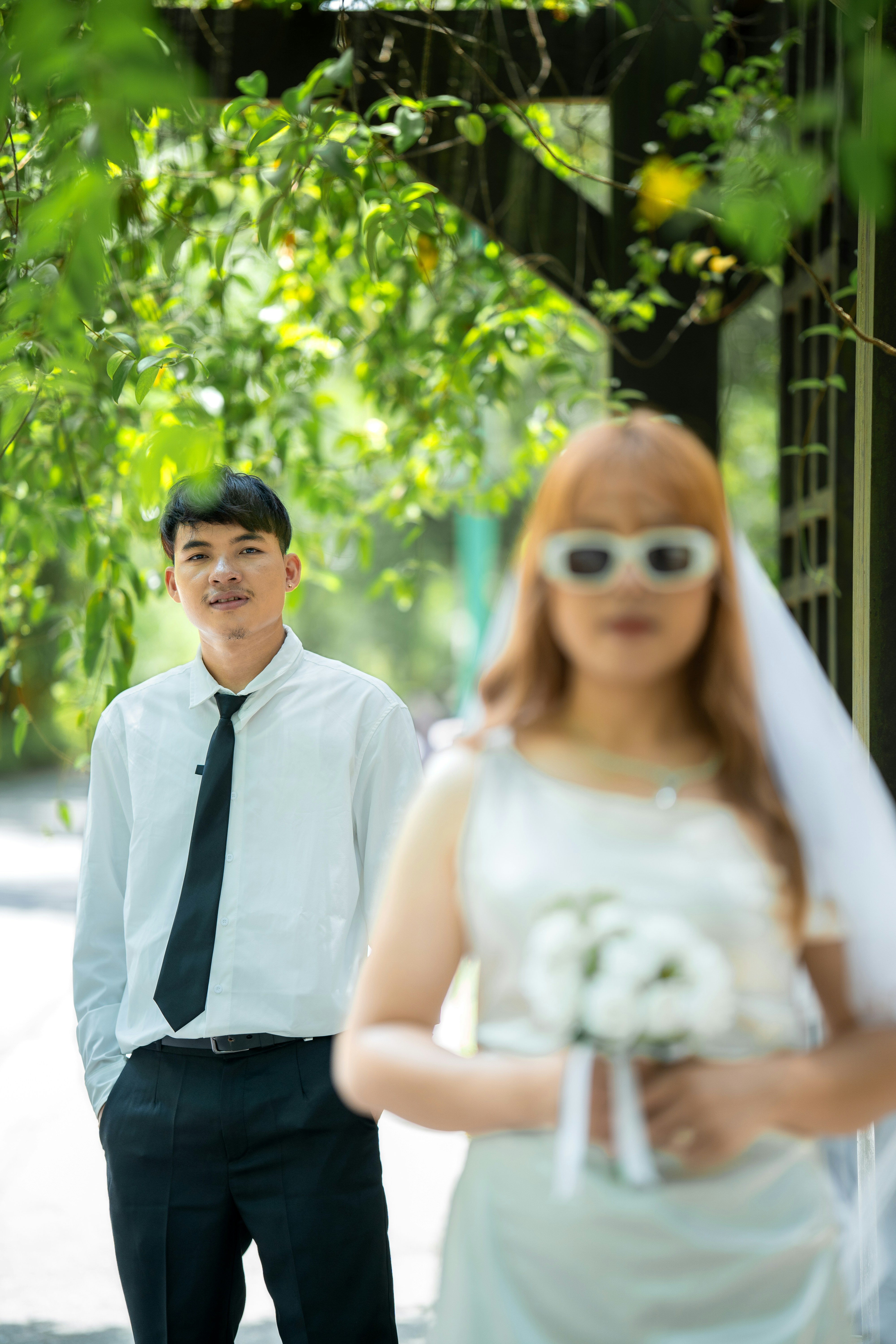 Bride and groom posing outdoors with greenery
