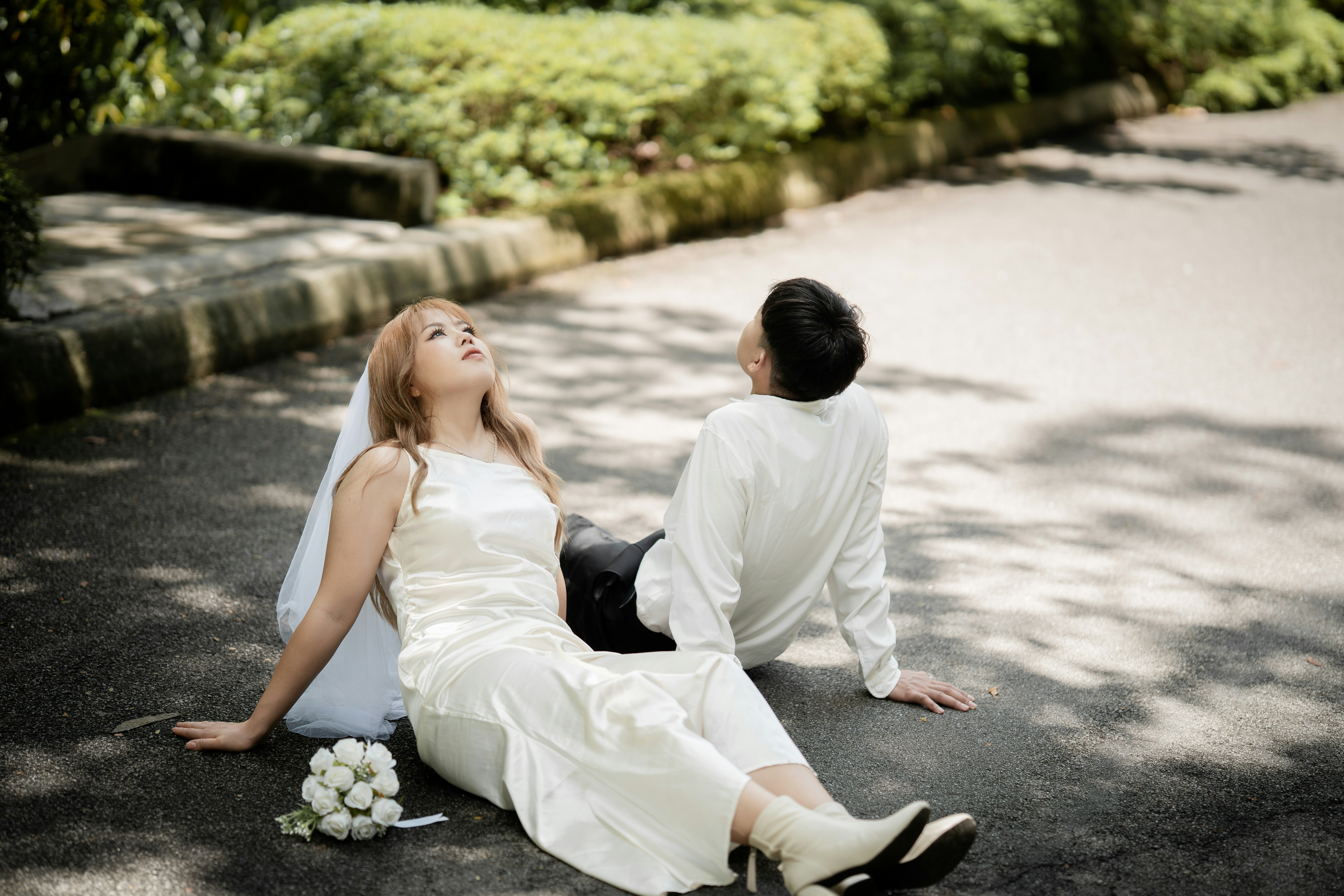 Bride and groom sitting on pavement outdoors
