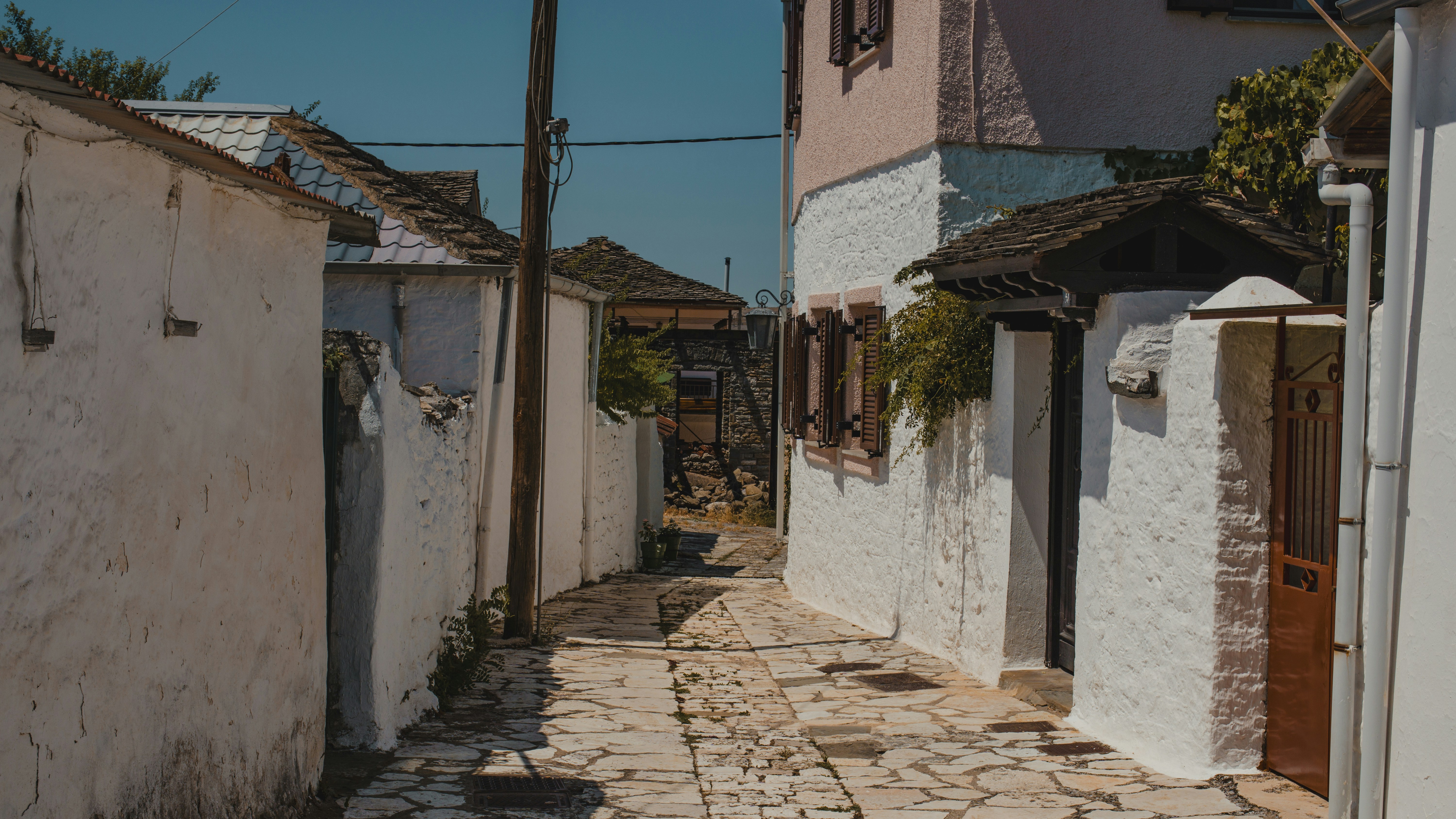Narrow cobblestone street between white buildings