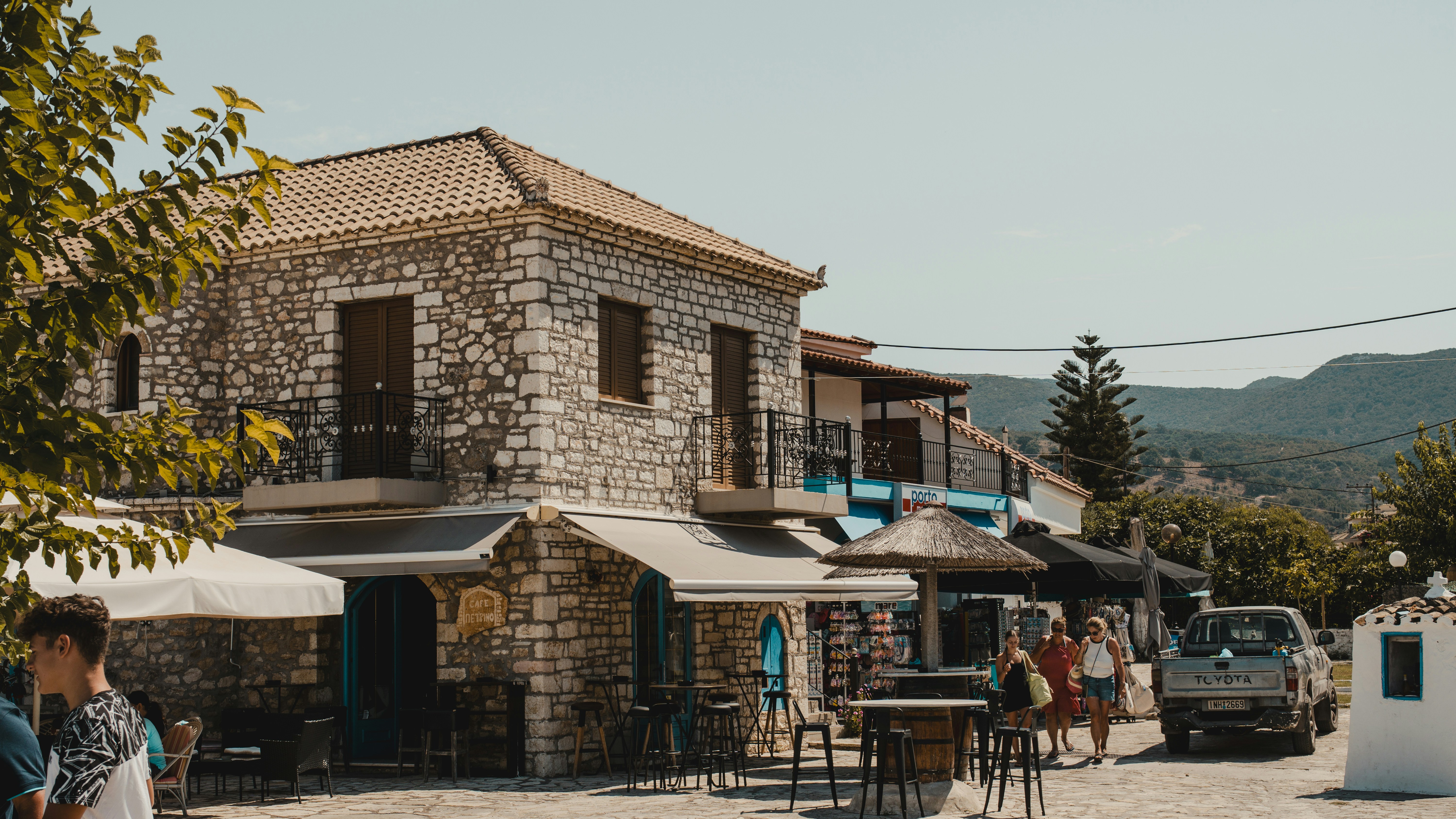 Stone buildings line a sunny street with people.