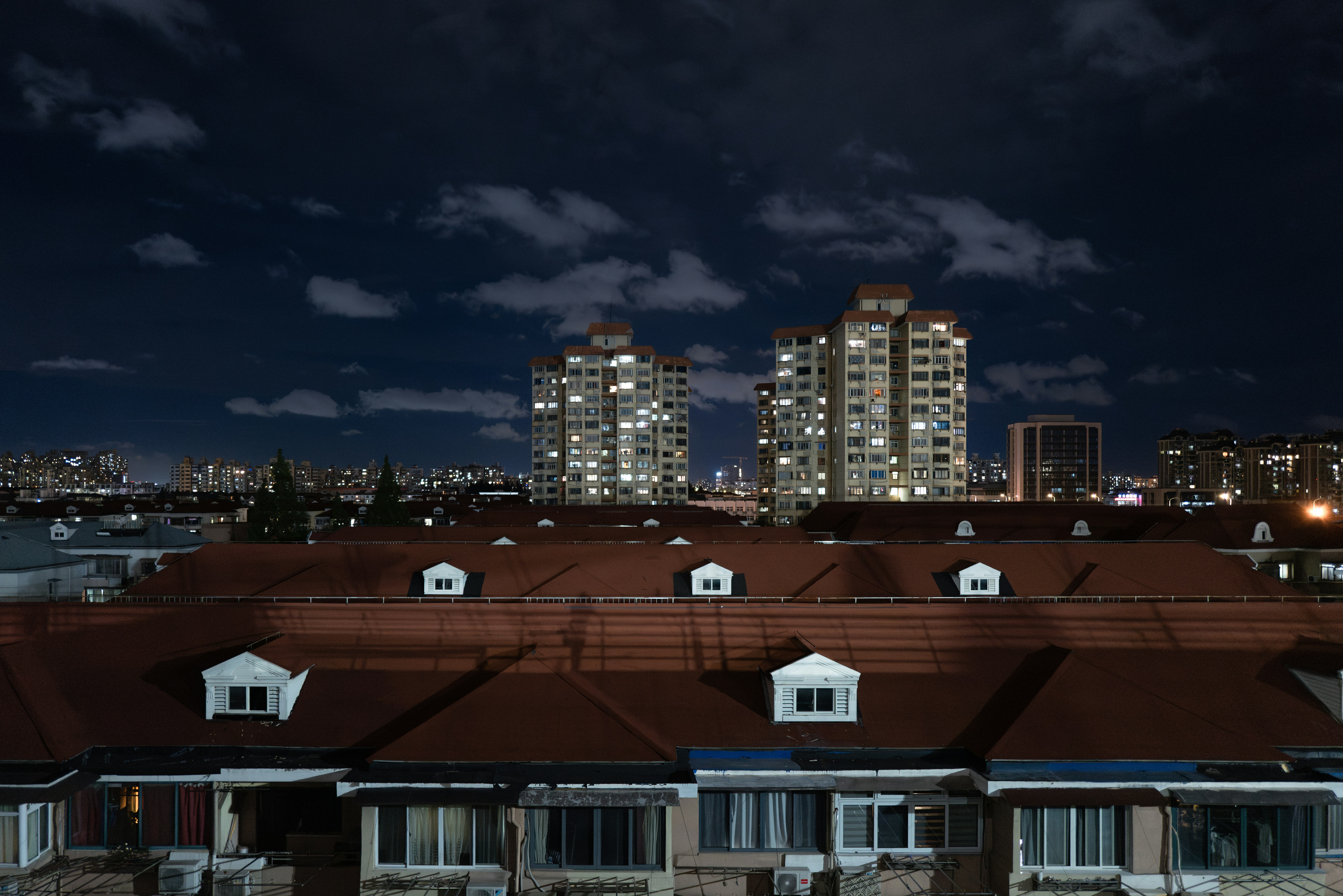 Red Roofs Under Nightfall: Dormers and Distant Towers