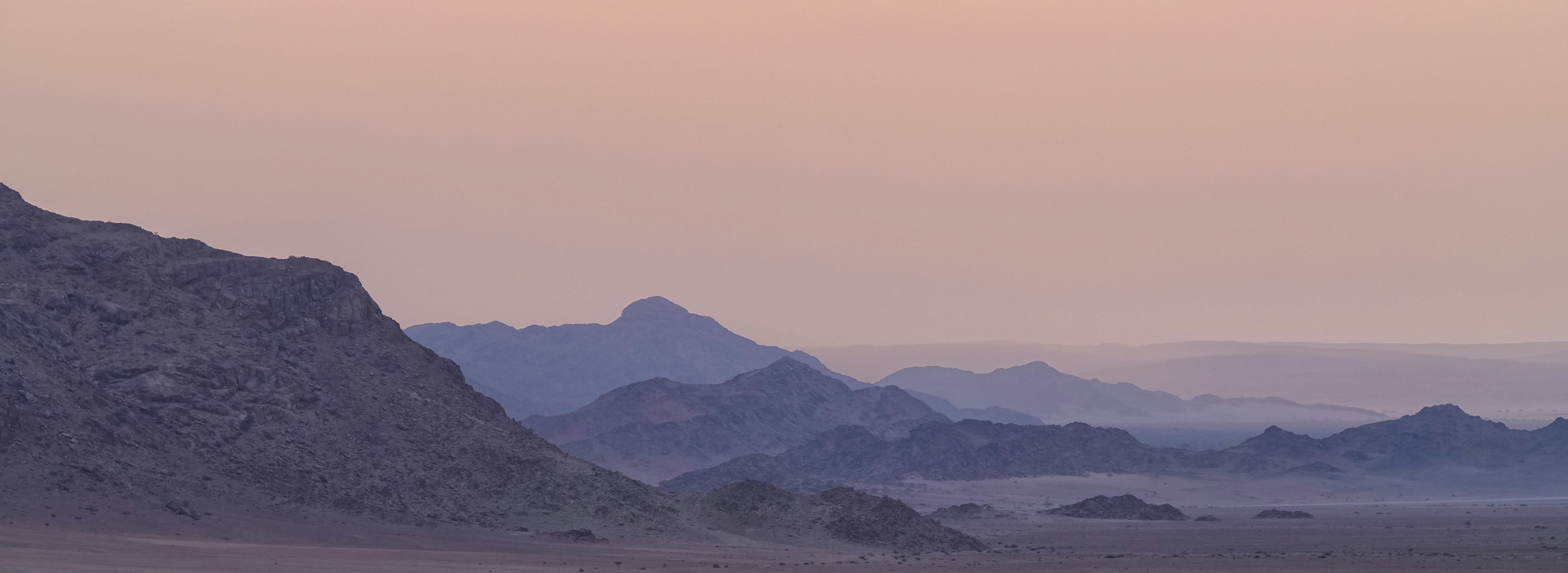 Layered mountains under a soft pink sky