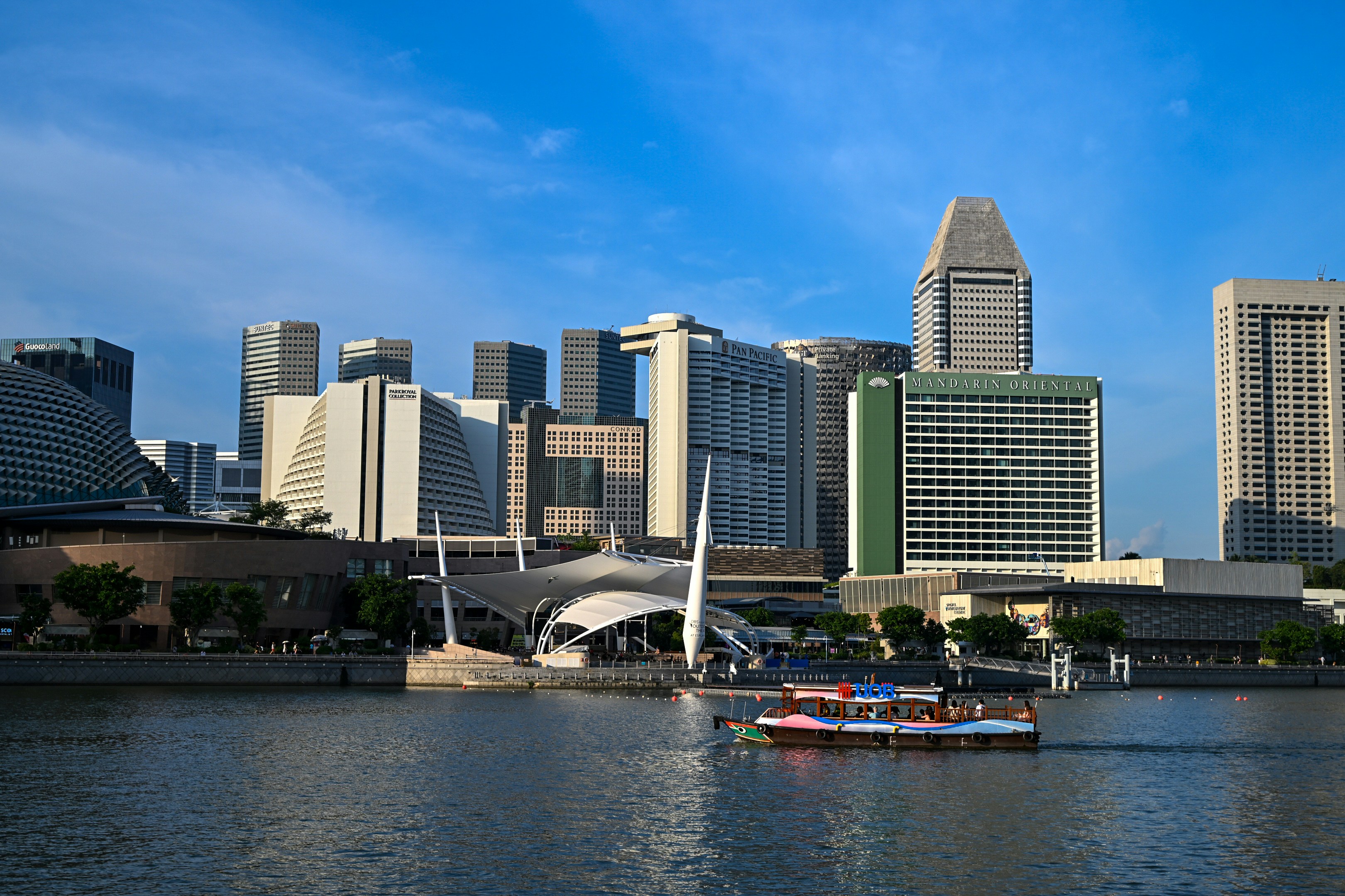 Modern cityscape with a river and boat under blue sky
