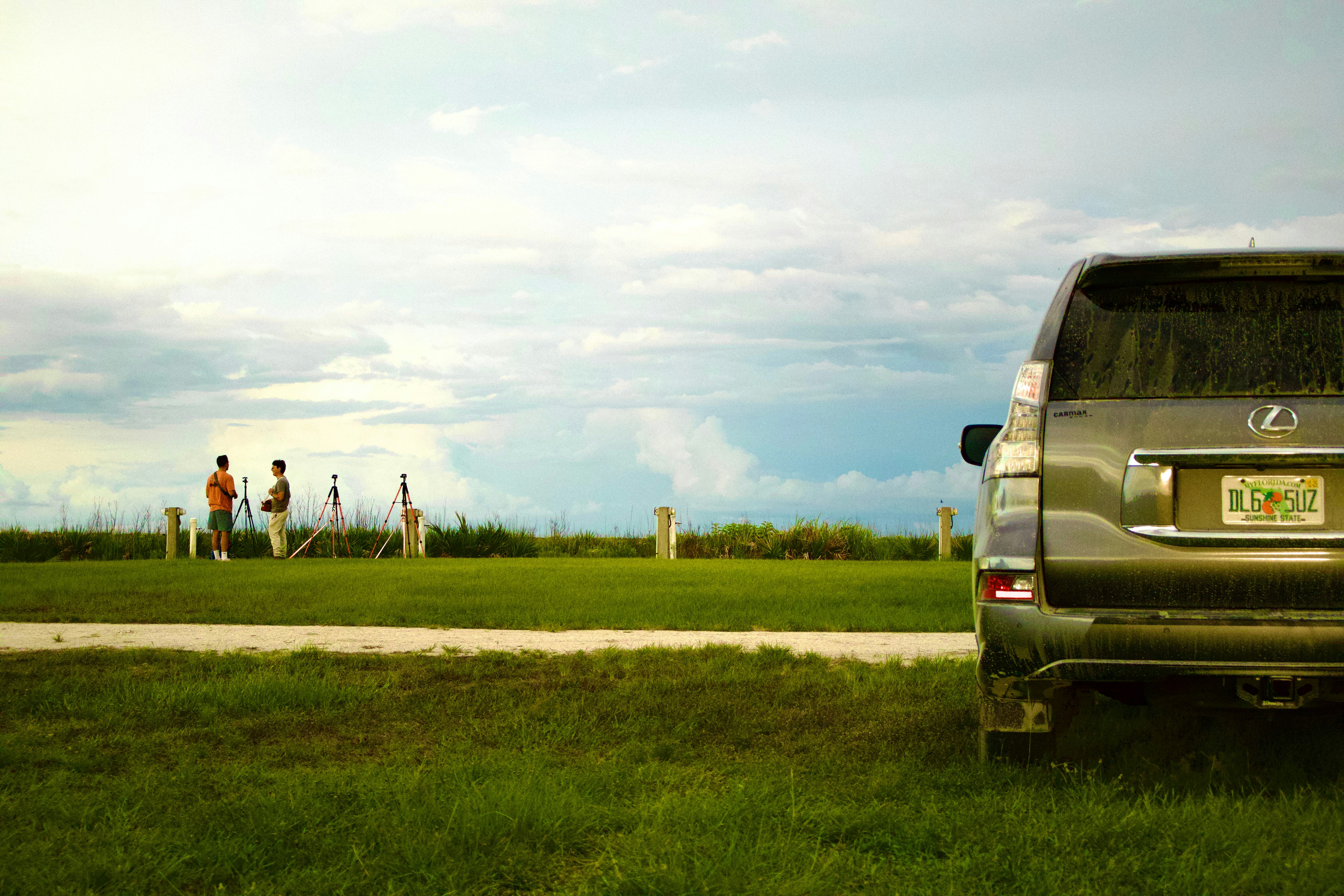 Tripod by the Field: Photographers and a Parked SUV Under an Overcast Sky