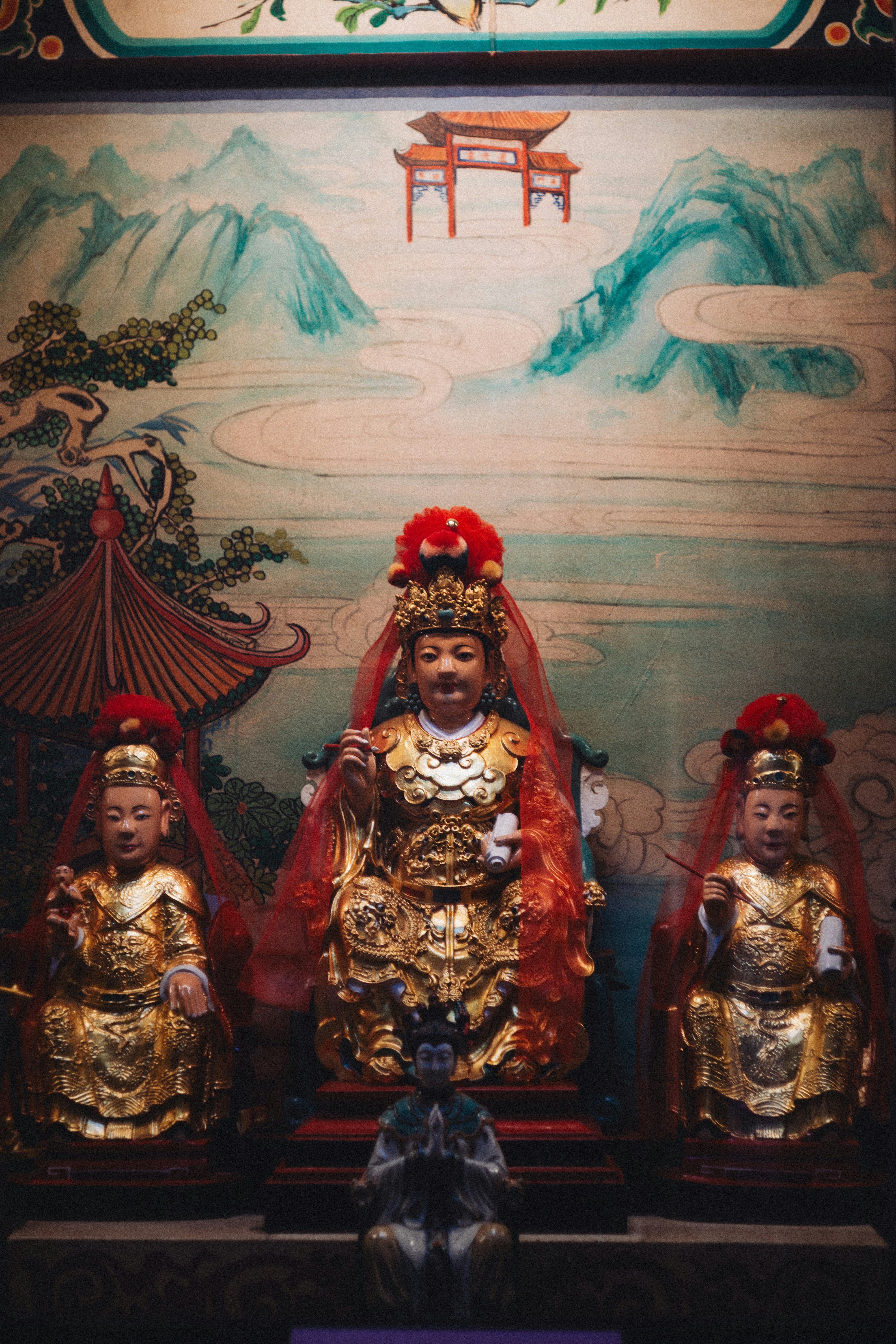 Three ornate golden statues in a shrine