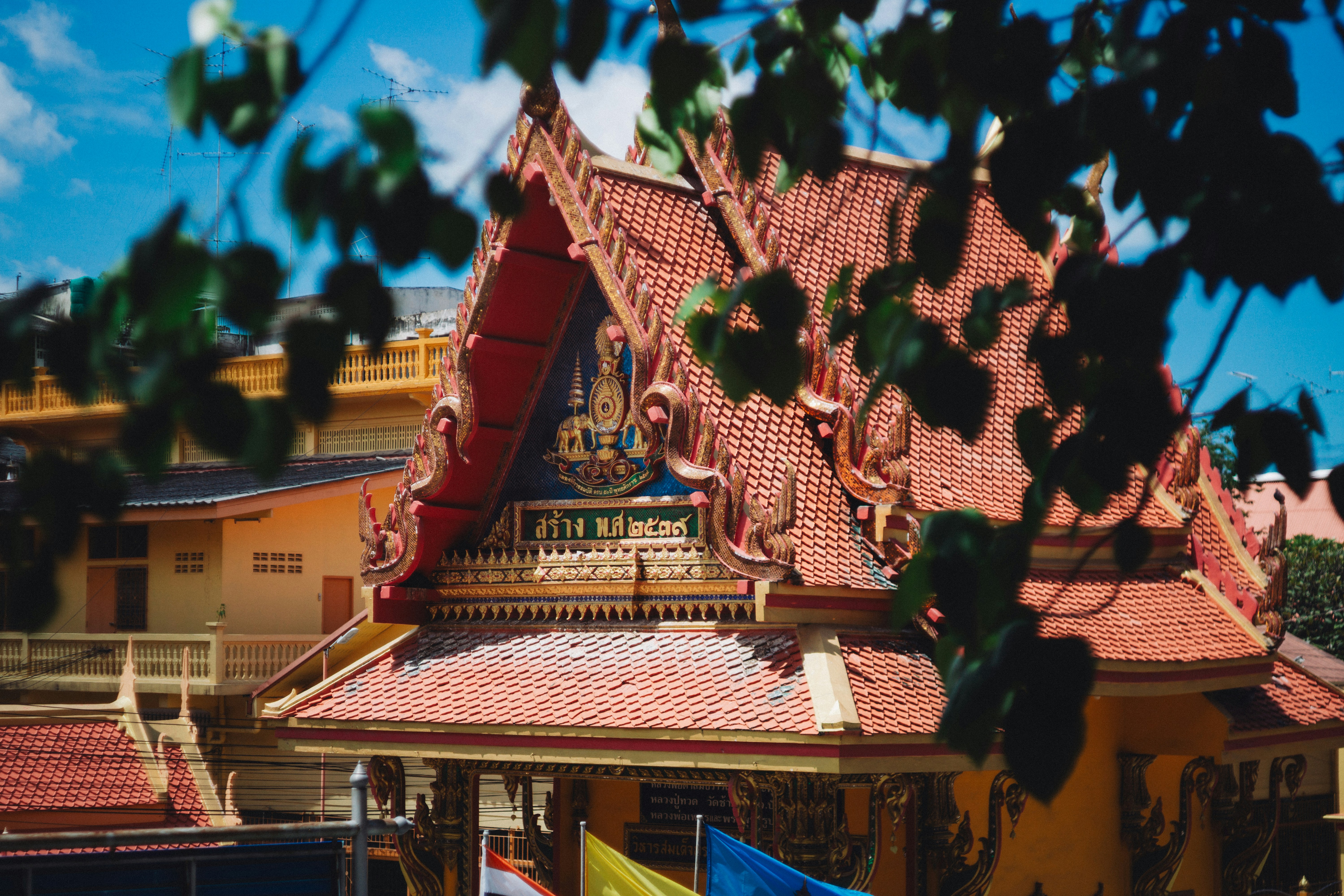 Ornate temple roof with blurred foliage in foreground.