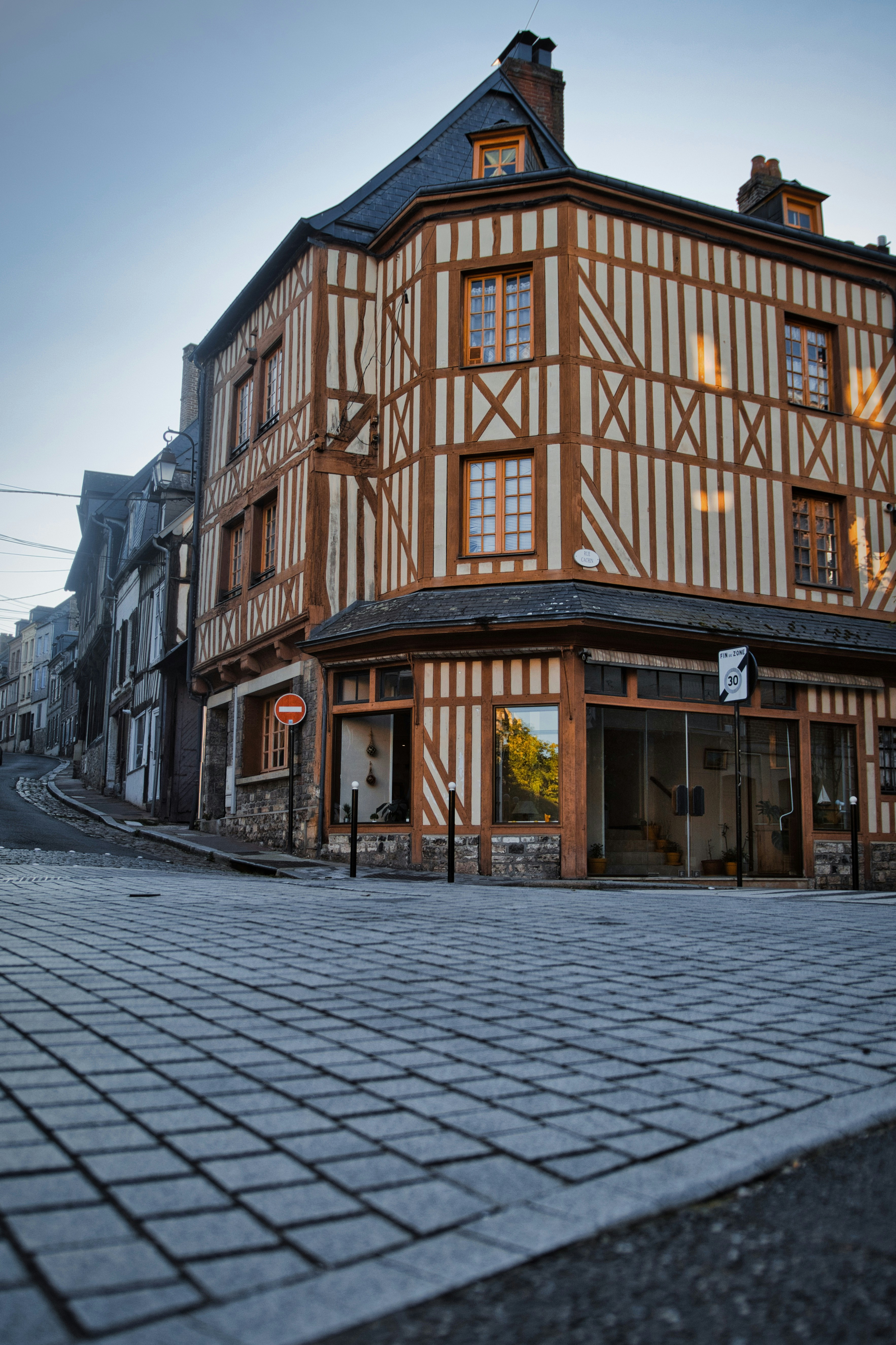 Historic timber-framed building with distinctive orange and white stripes, set against a cobblestone street in a quaint town.