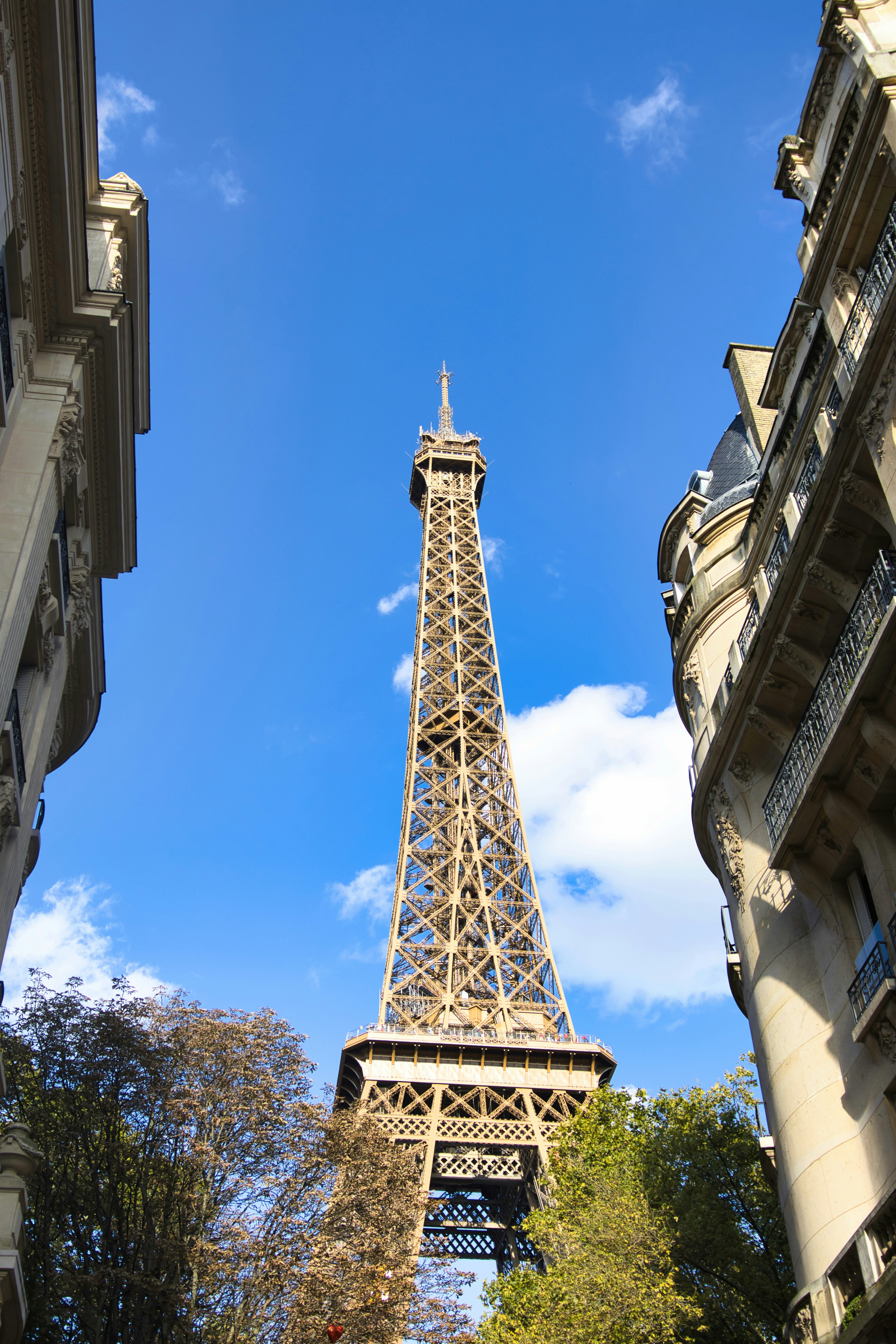 Eiffel tower viewed from below between buildings.