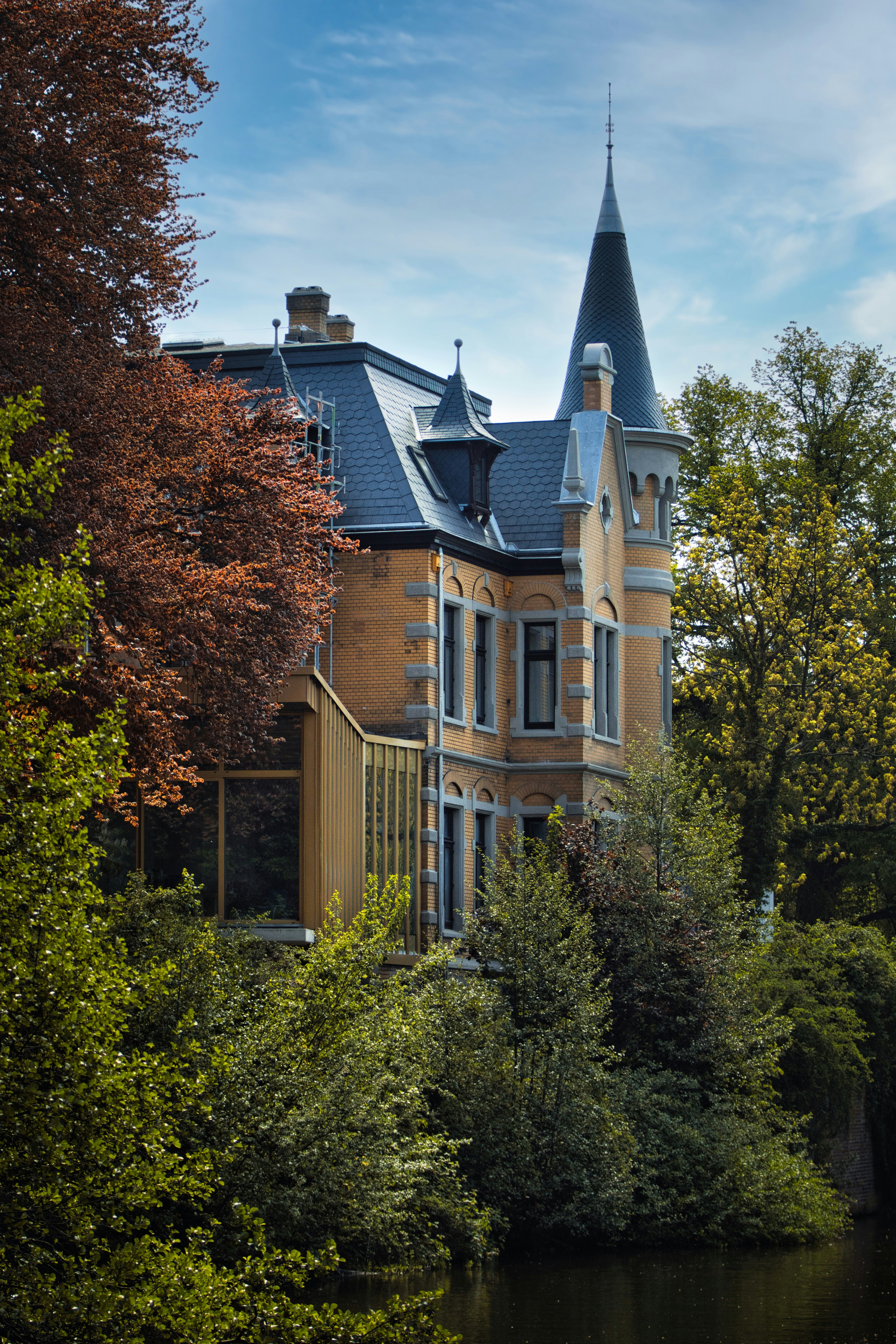 Ornate yellow building with a turret surrounded by trees.