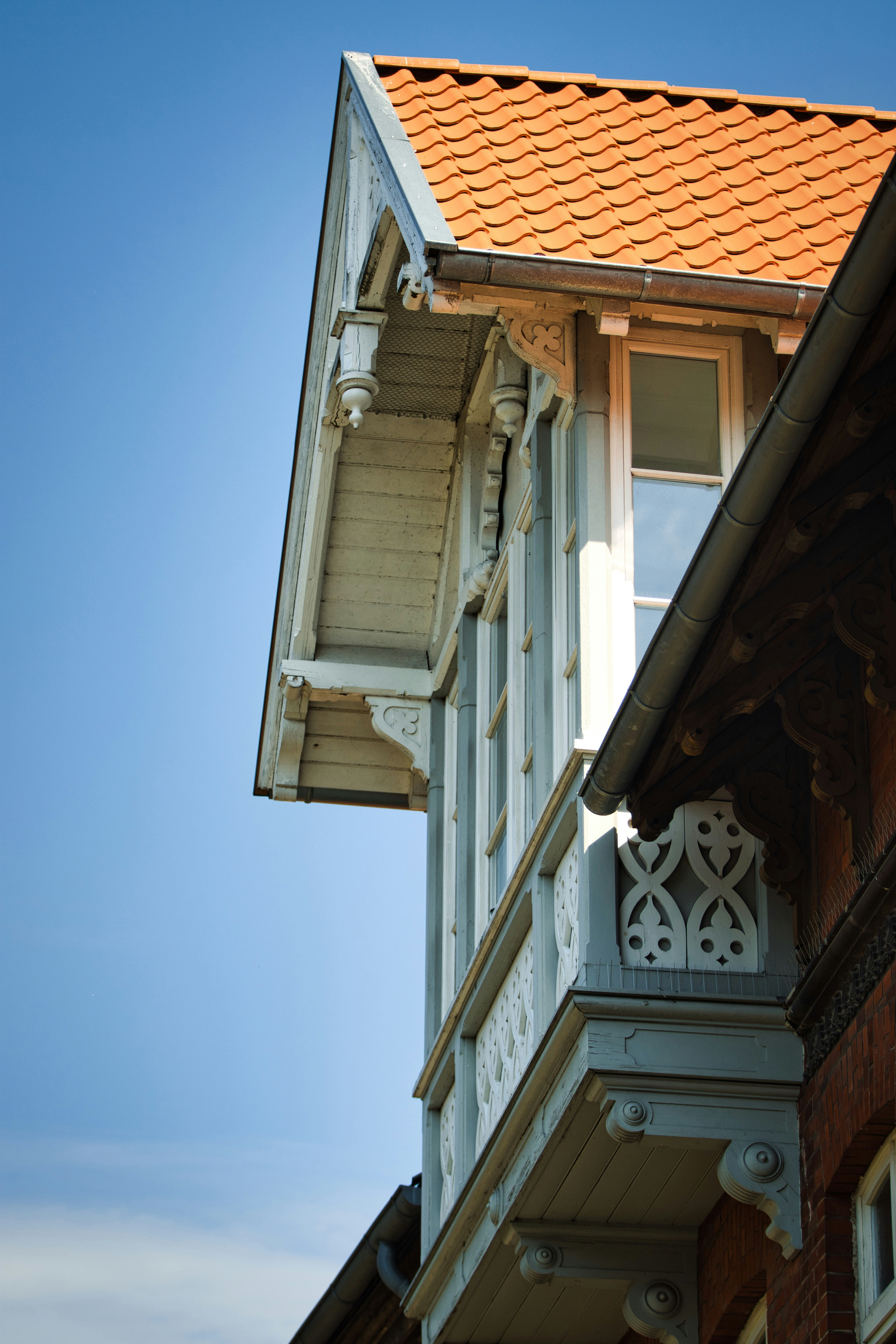 Intricate wooden balcony and roofline of a historic building against a blue sky.