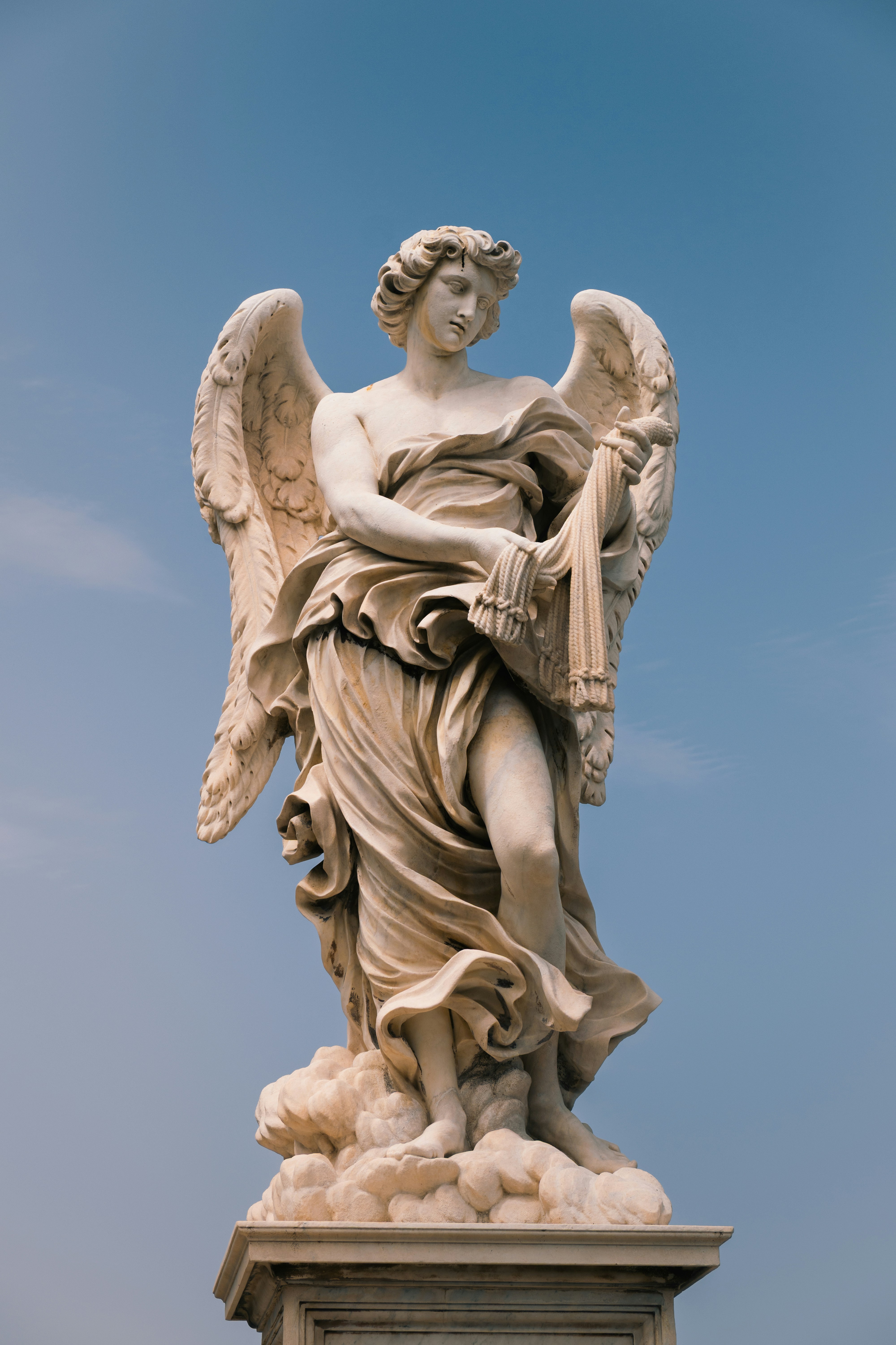 Marble angel statue against a blue sky.