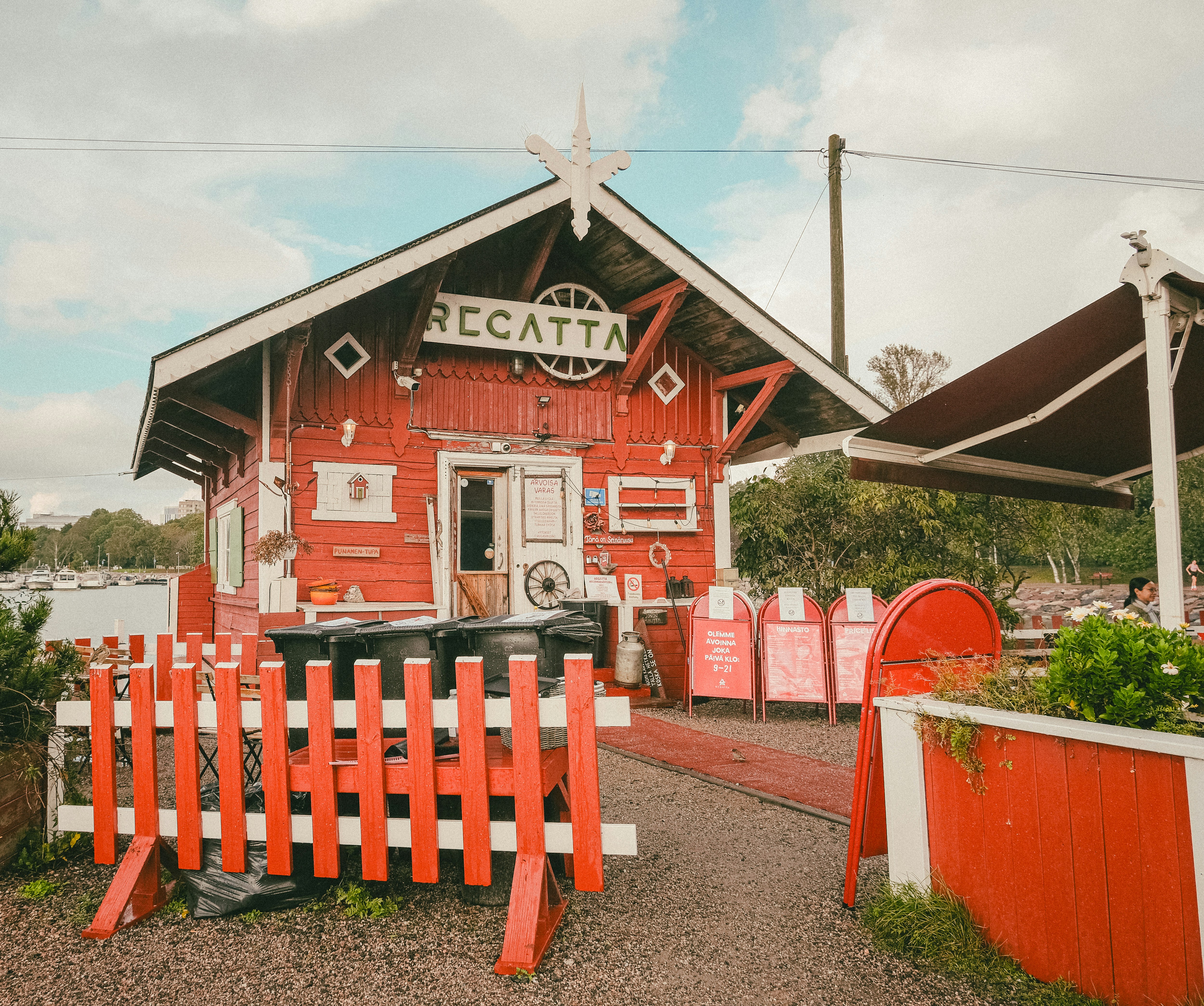 Cafe Regatta is located by the sea, close to Sibelius monument in Töölö. The traditional red cottage cafe has brought a part of Finnish countryside to the middle of Helsinki. | Red wooden building with "reccatta" sign