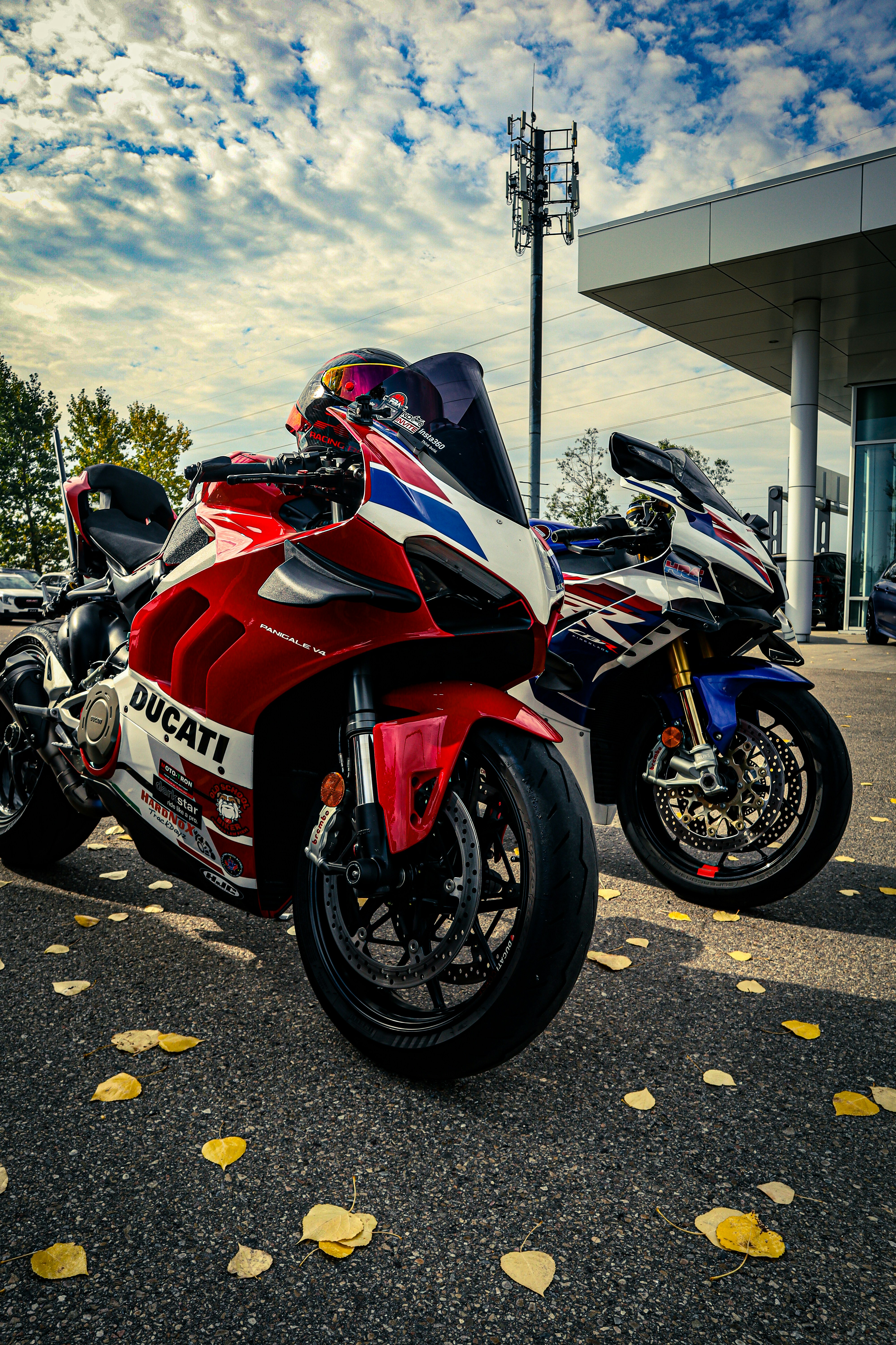 Two high-performance motorcycles, a Ducati and a sportbike, parked under a dynamic sky, showcasing their sleek designs and vibrant colors.