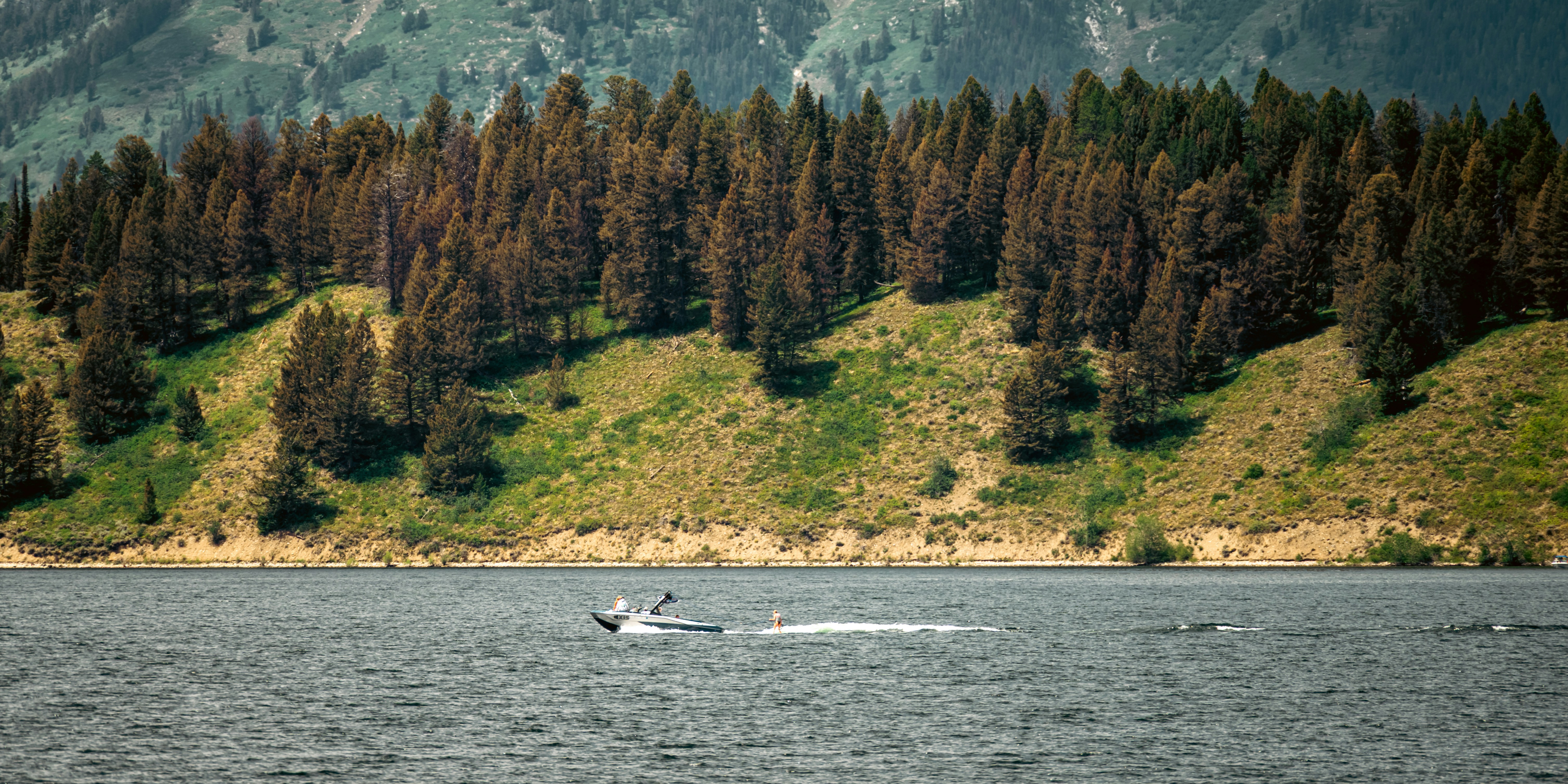 People on a boat in a lake with forested hills.