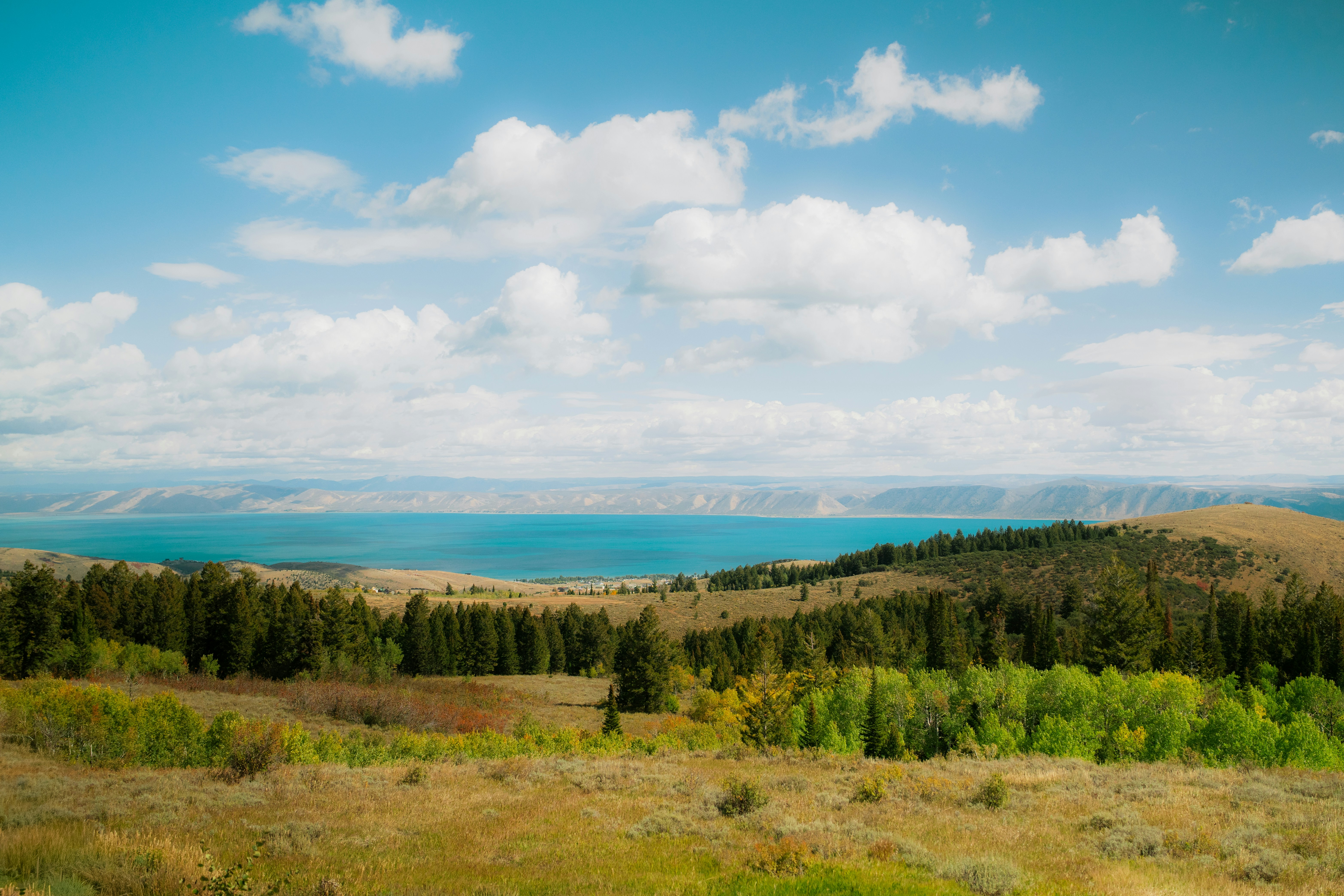 Rolling hills meet a vast blue lake under clouds