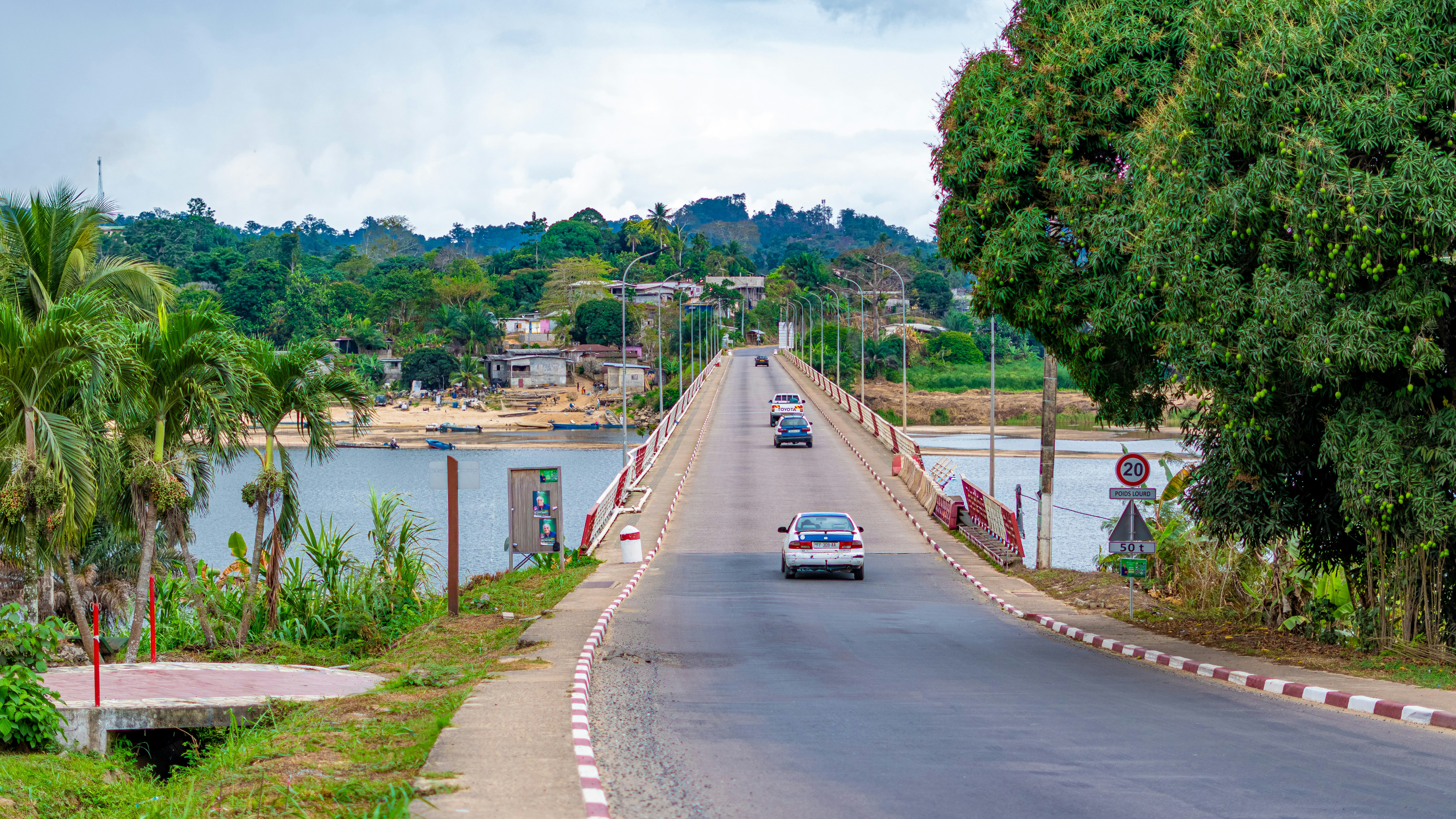 Pont d'Adouma | Cars crossing a bridge over a wide river.