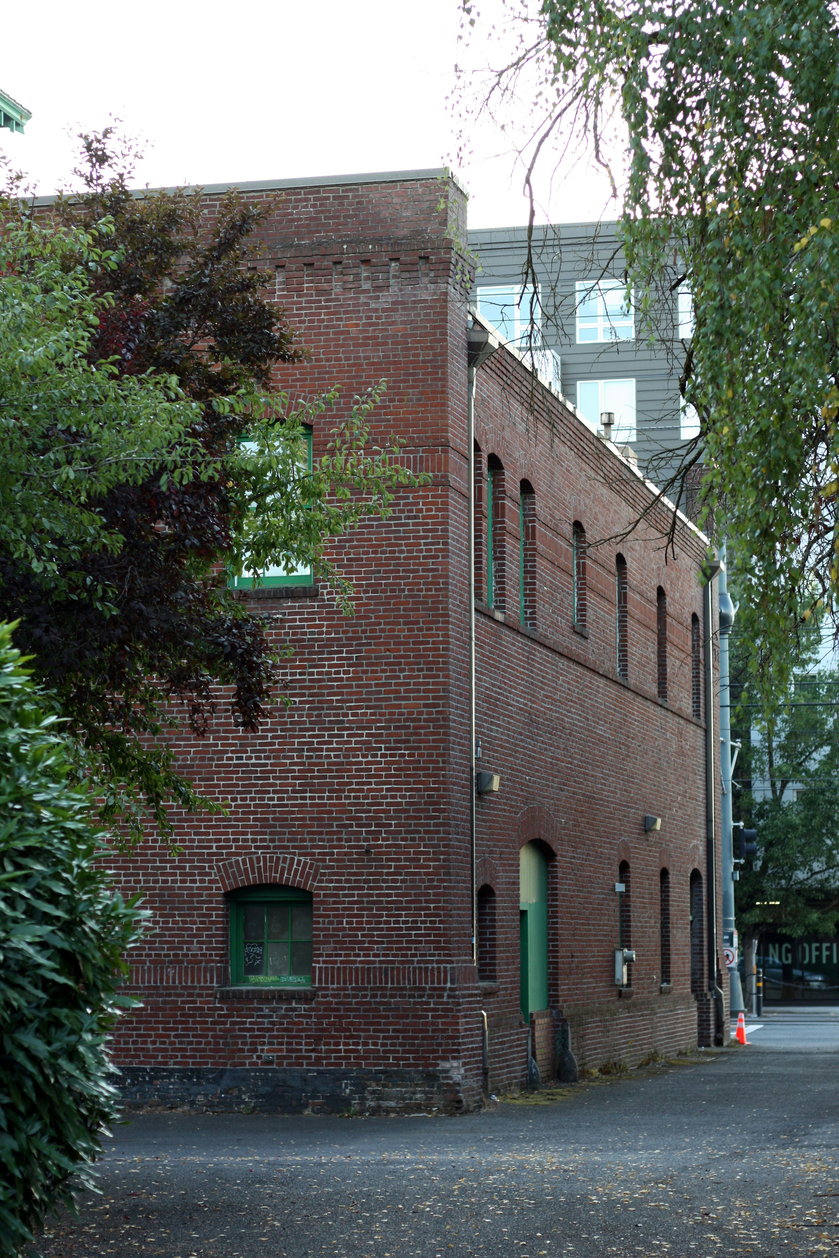 Brick building with green windows and trees.