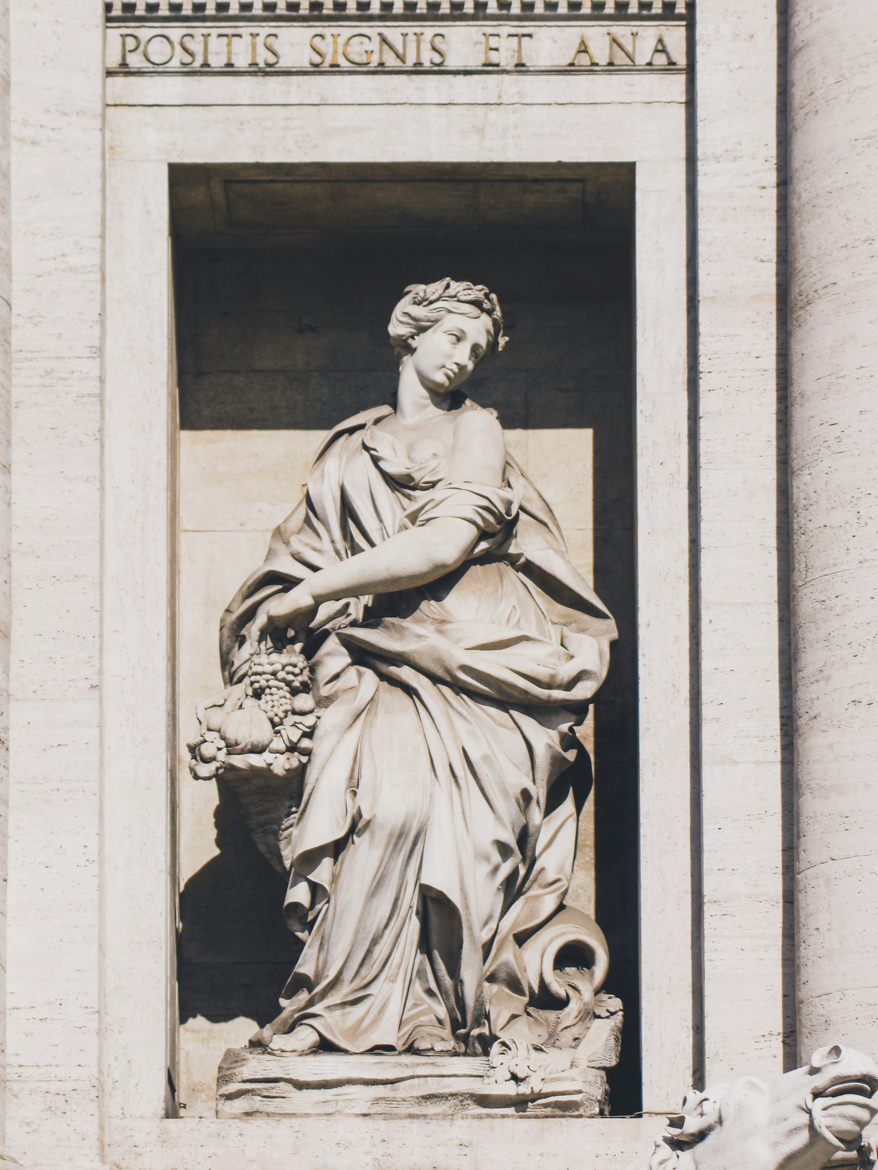 Sculpture representing Abundance at the Trevi Fountain | Marble statue of a woman holding a basket of flowers.