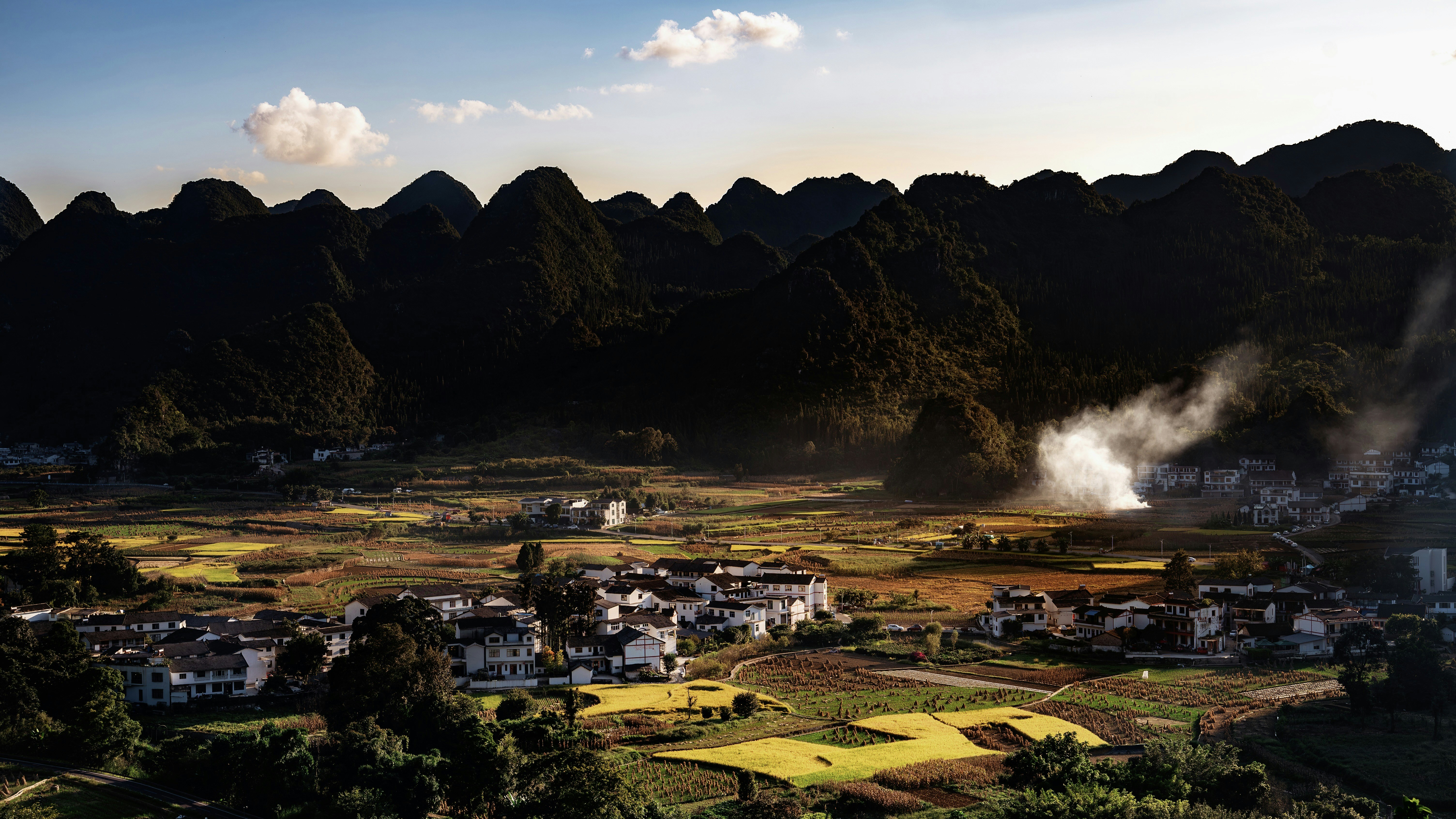 Rural village nestled among rolling hills at sunset.