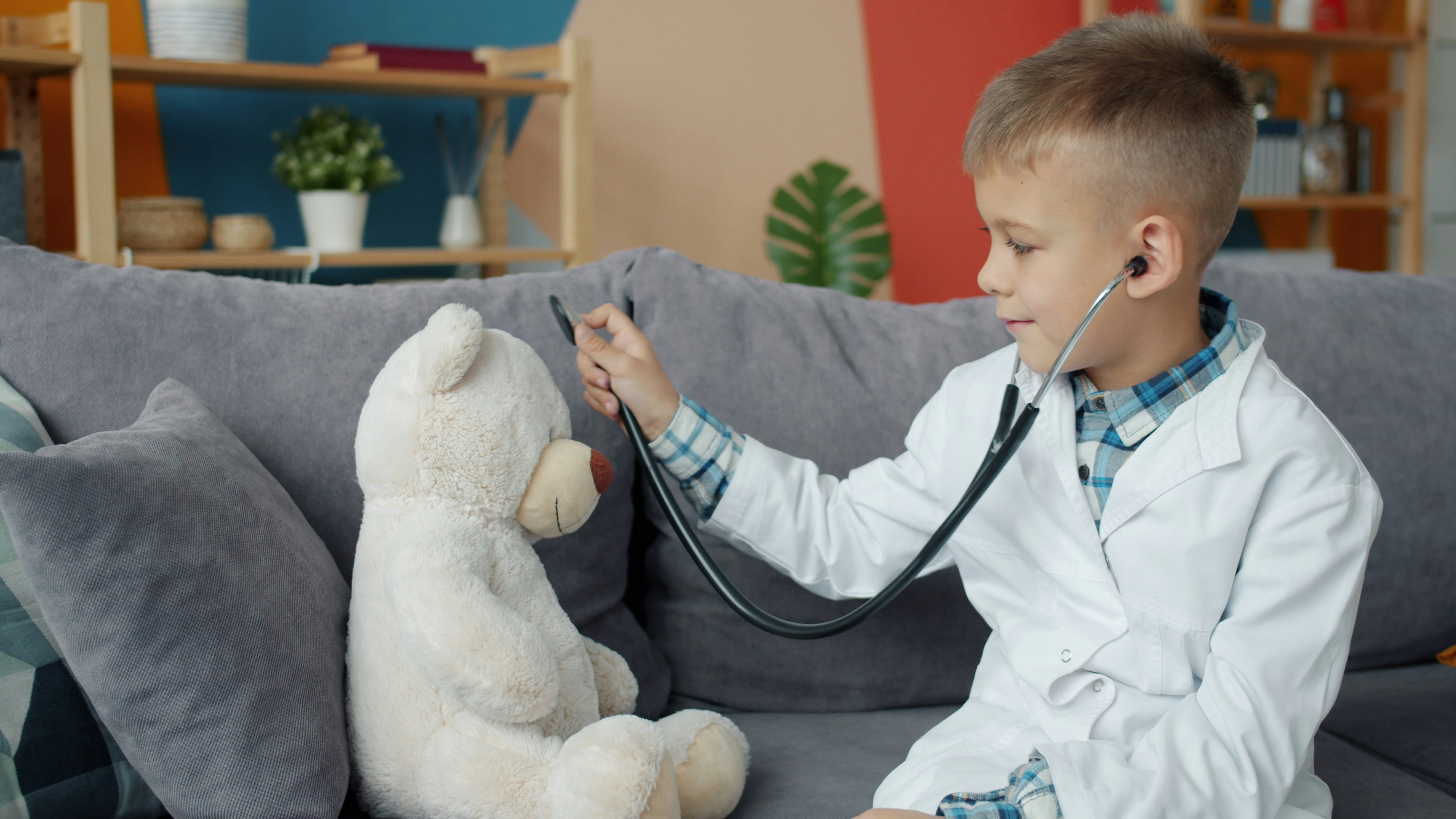 Niño en bata de médico escucha al osito de peluche foto – Imagen de ...