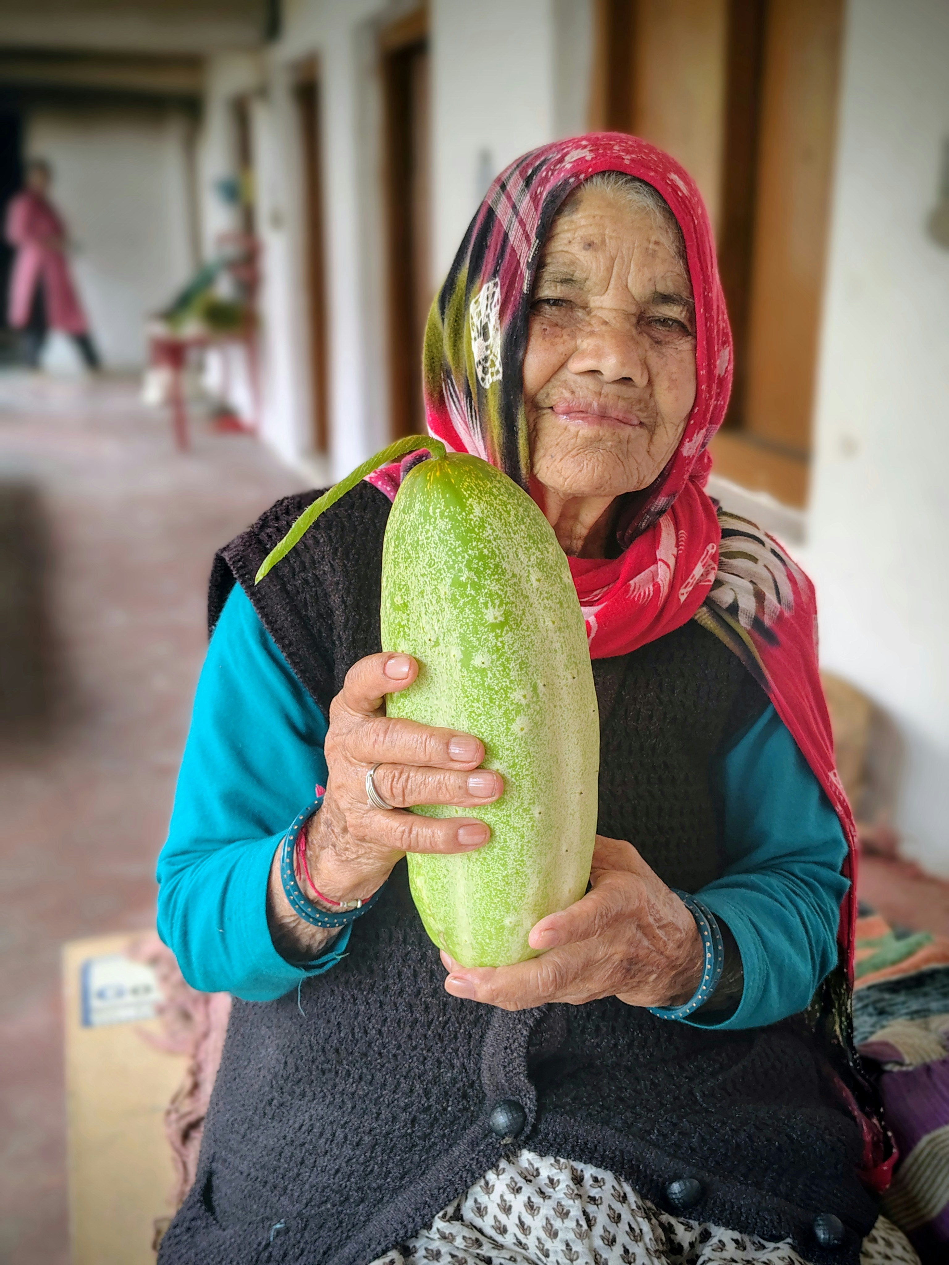 Elderly woman holds a large cucumber