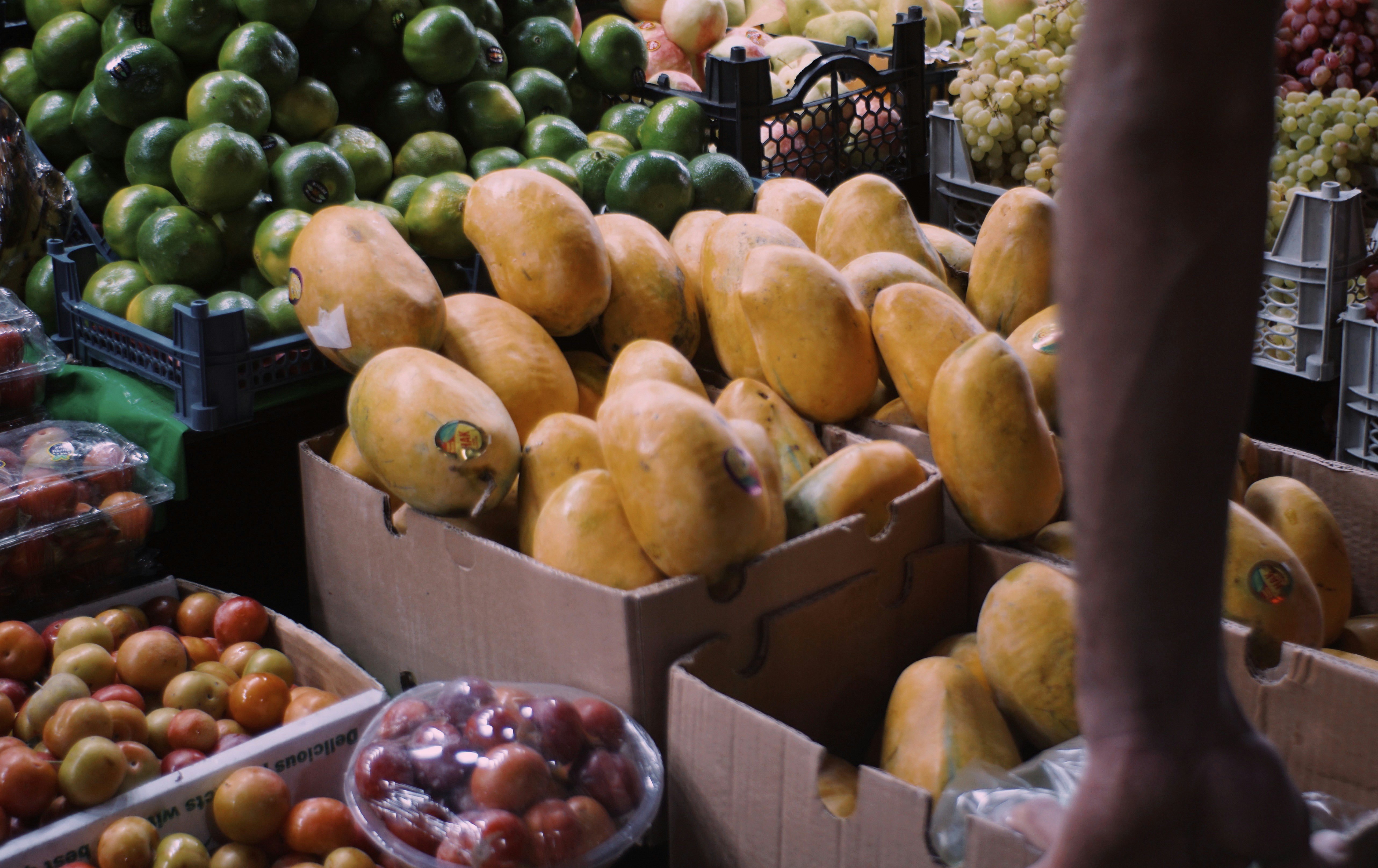 Reaching for a taste of sunshine. | Fresh papayas and other fruits displayed at market.