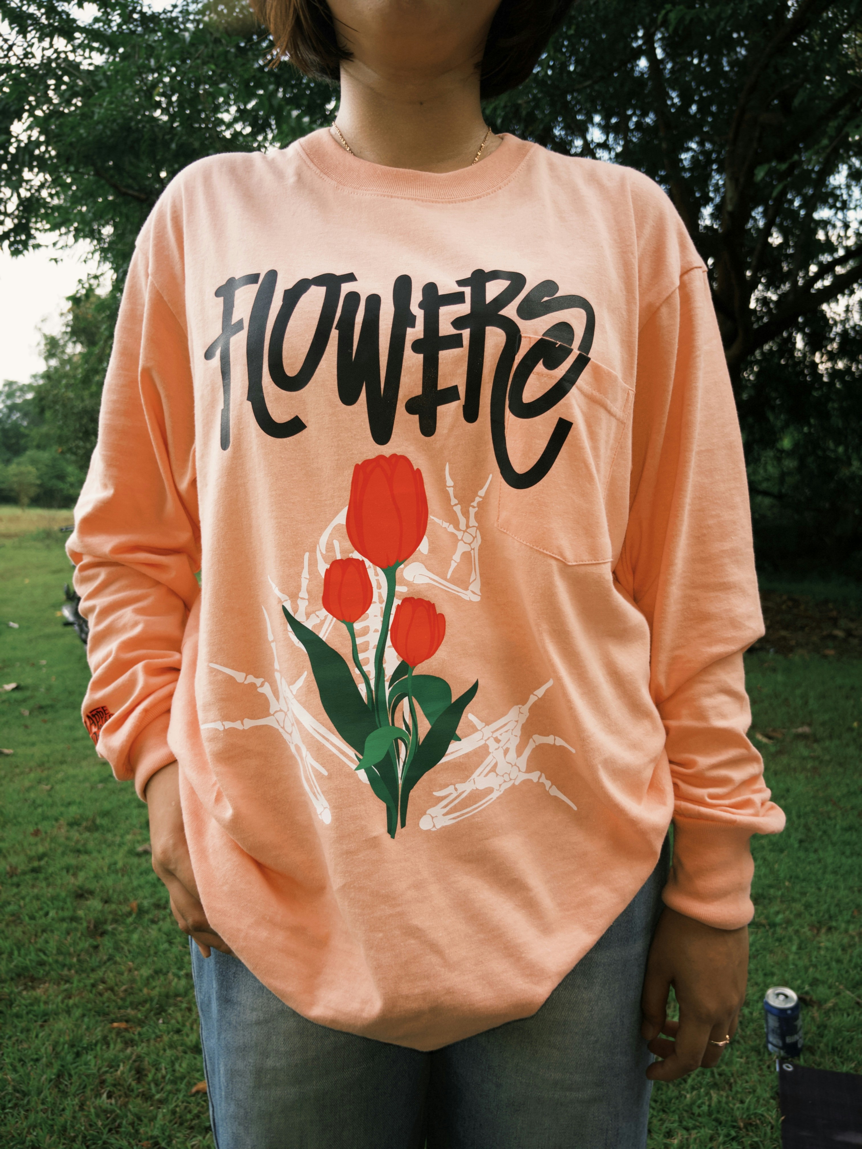 Peach long-sleeve shirt with floral graphic.