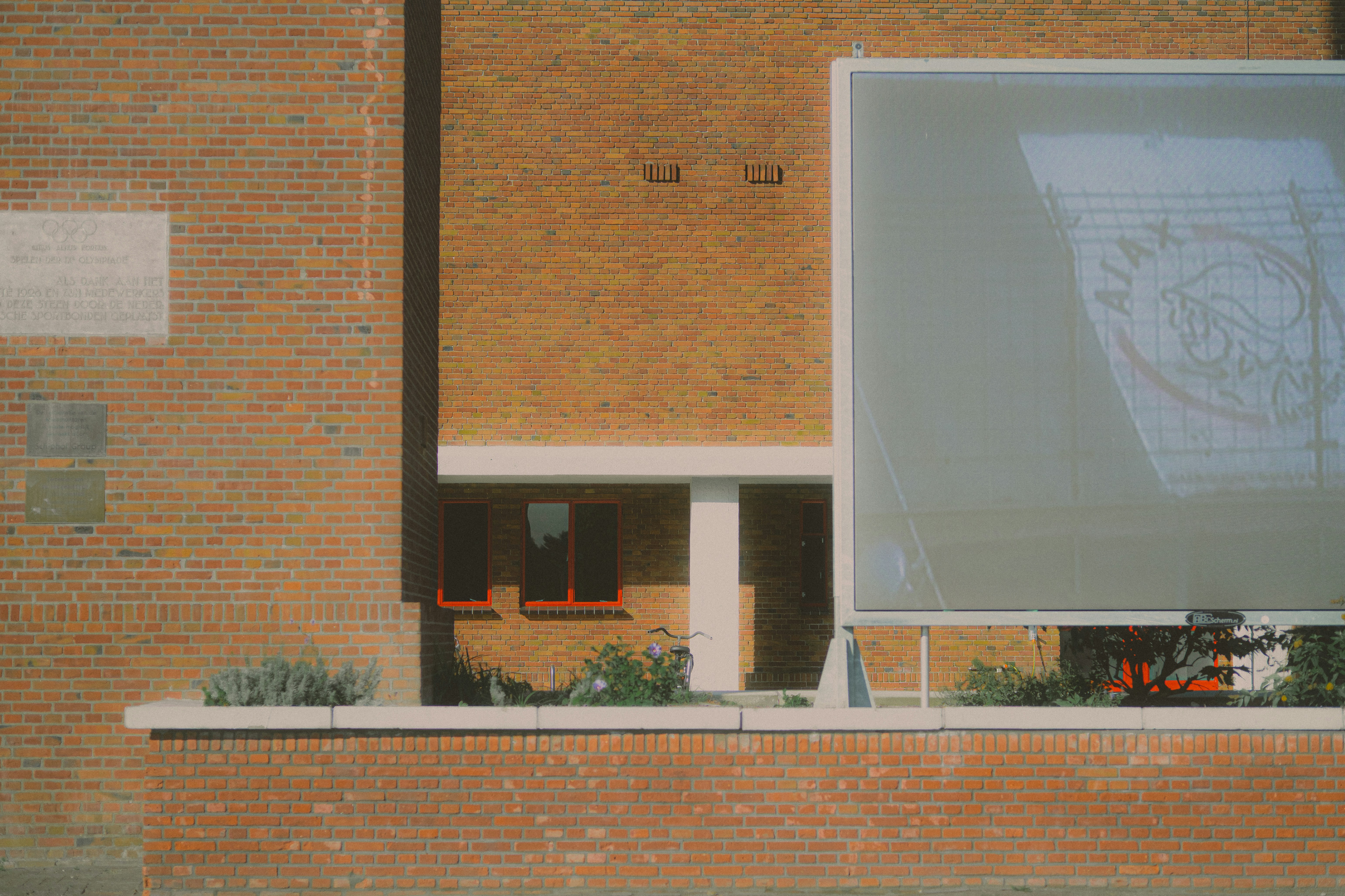 Brick walls at the Olympia Stadium in Amstedam | Modern brick building with large glass panel