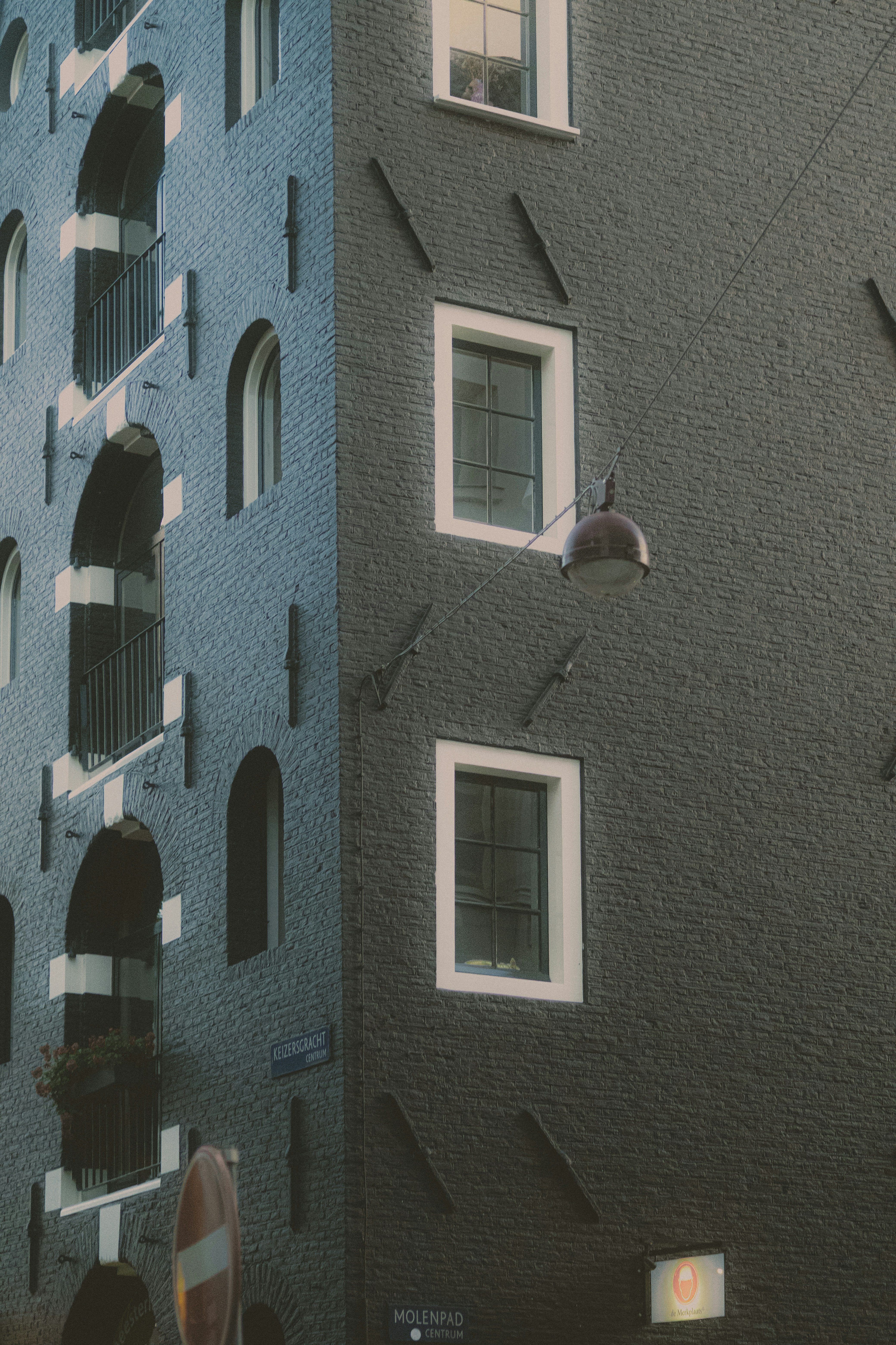 A pitch black house facade in Amsterdam | Two brick buildings with distinct window styles.