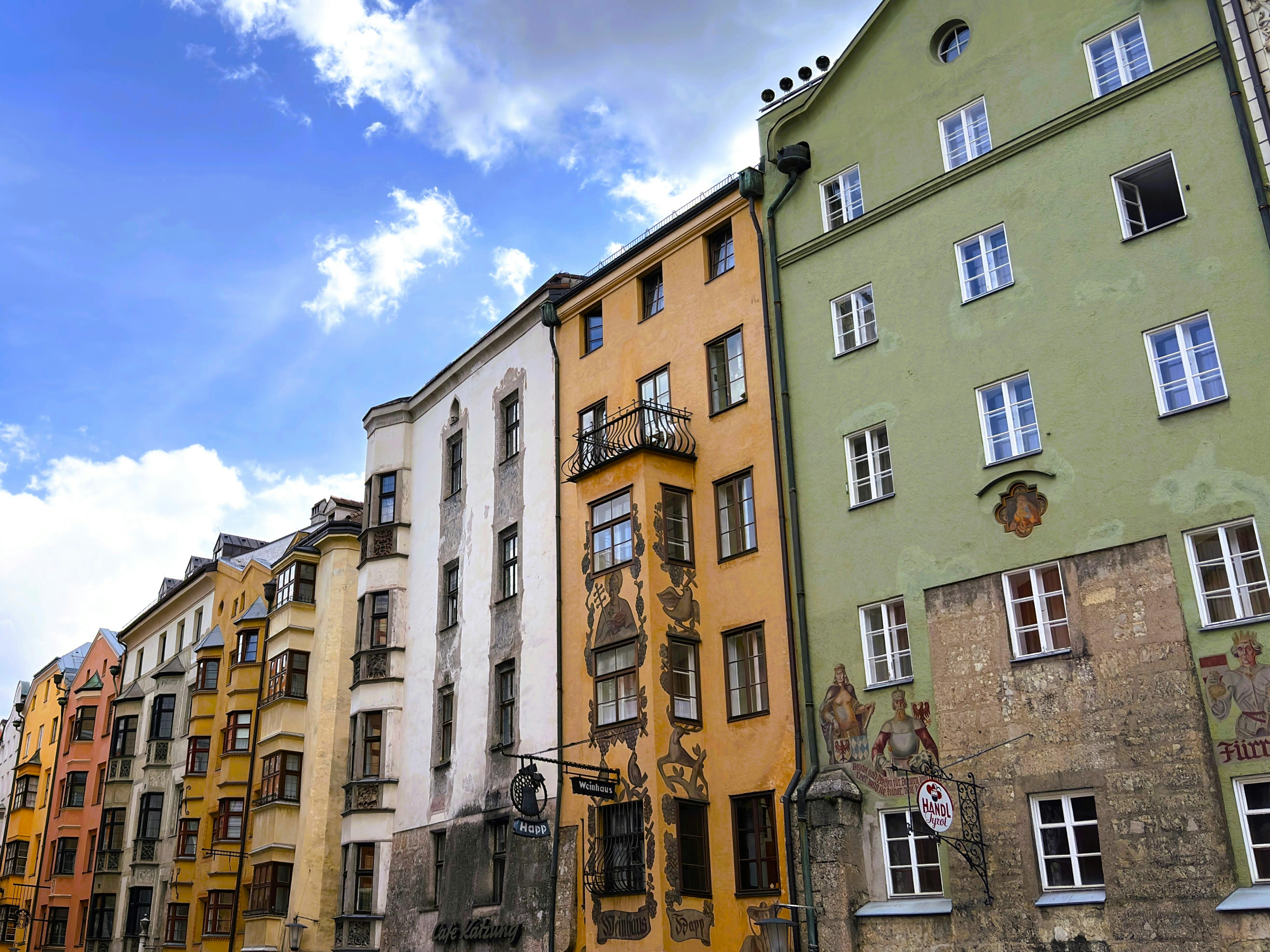 Vibrant buildings line a historic street, showcasing a blend of architectural styles and colors. The scene captures the essence of urban charm and history.