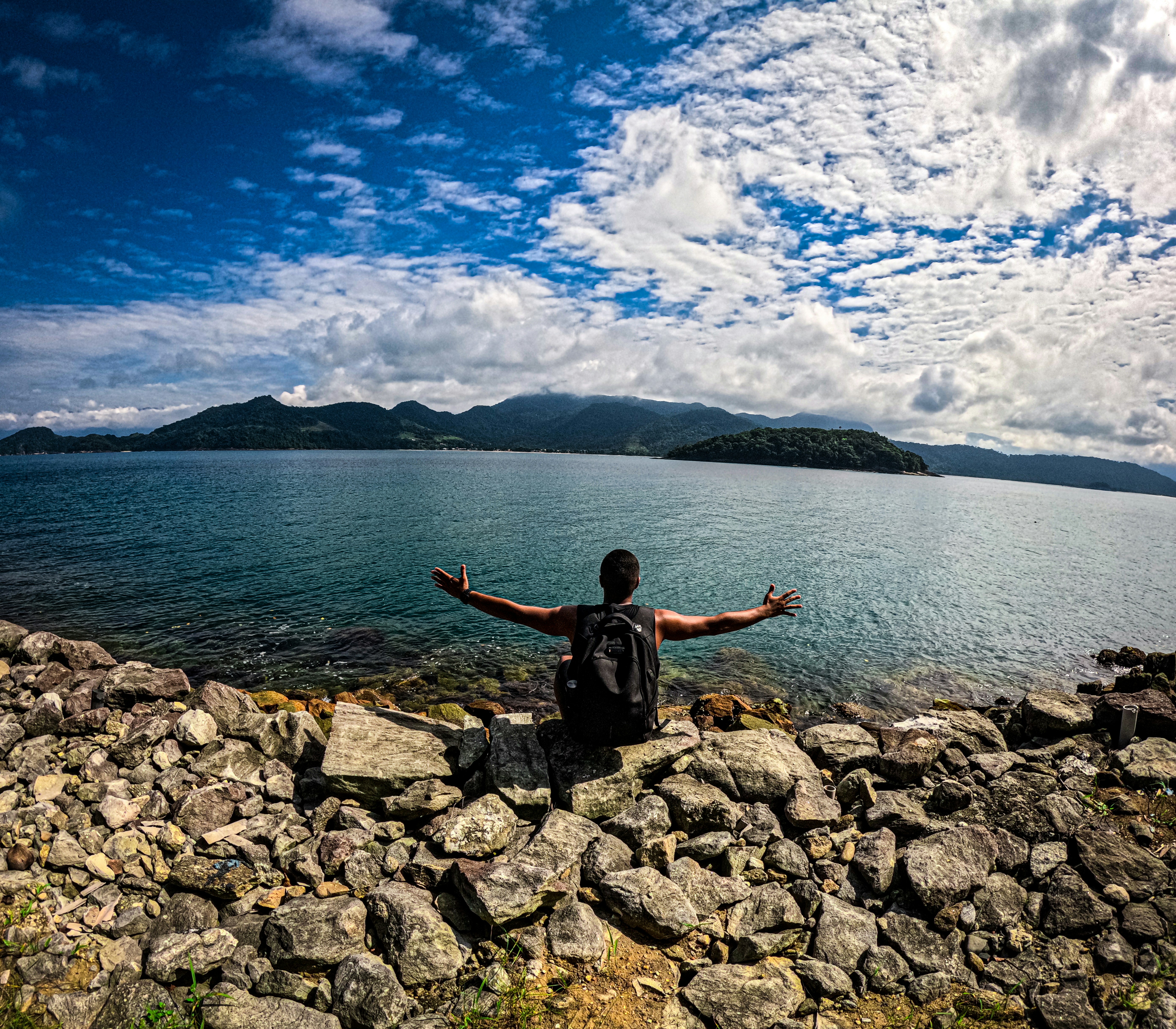 Man with arms outstretched by the sea