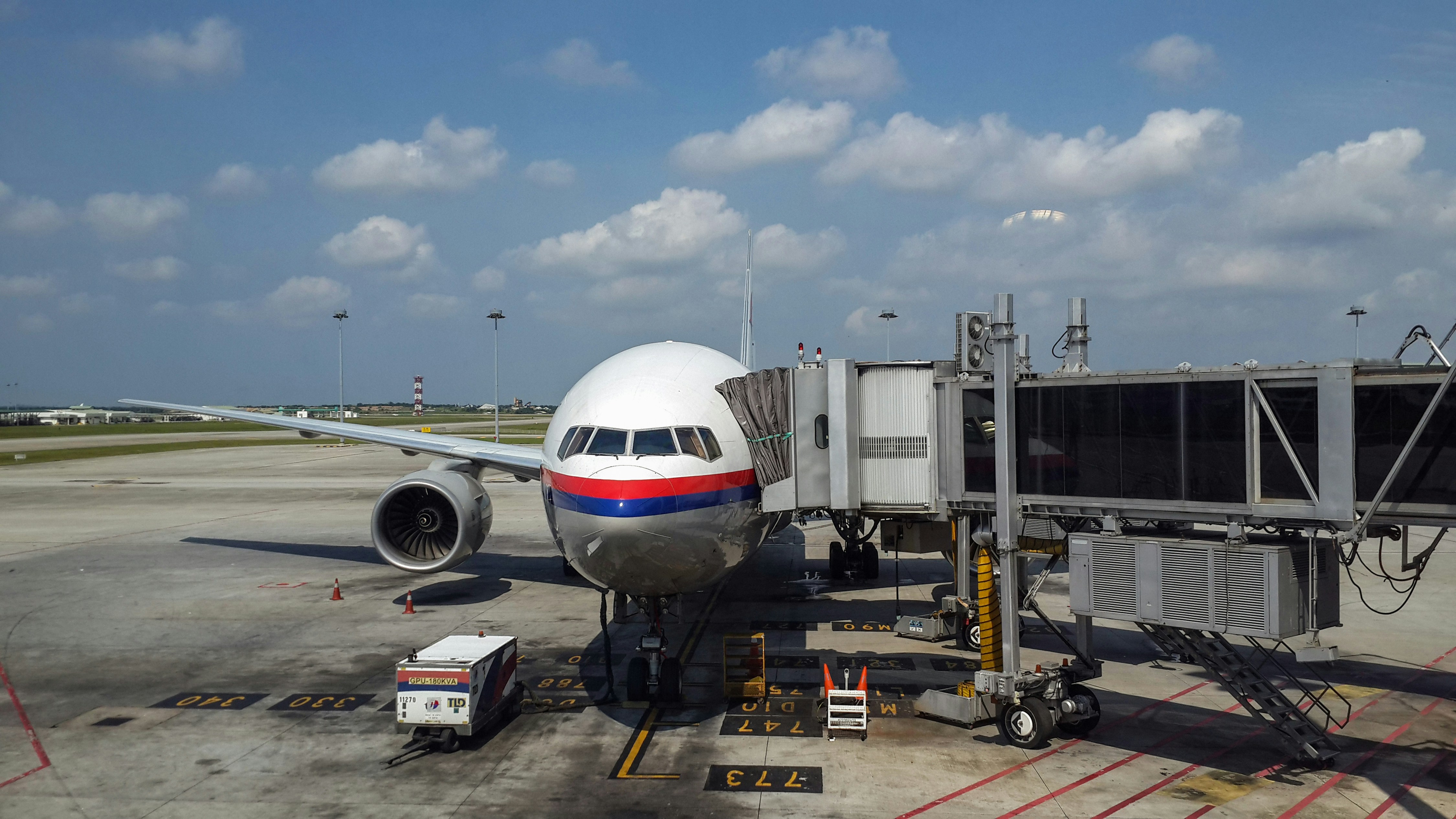 Malaysia Air boeing 777 in park position and jetway attached in airport | Airplane connected to a jet bridge at airport