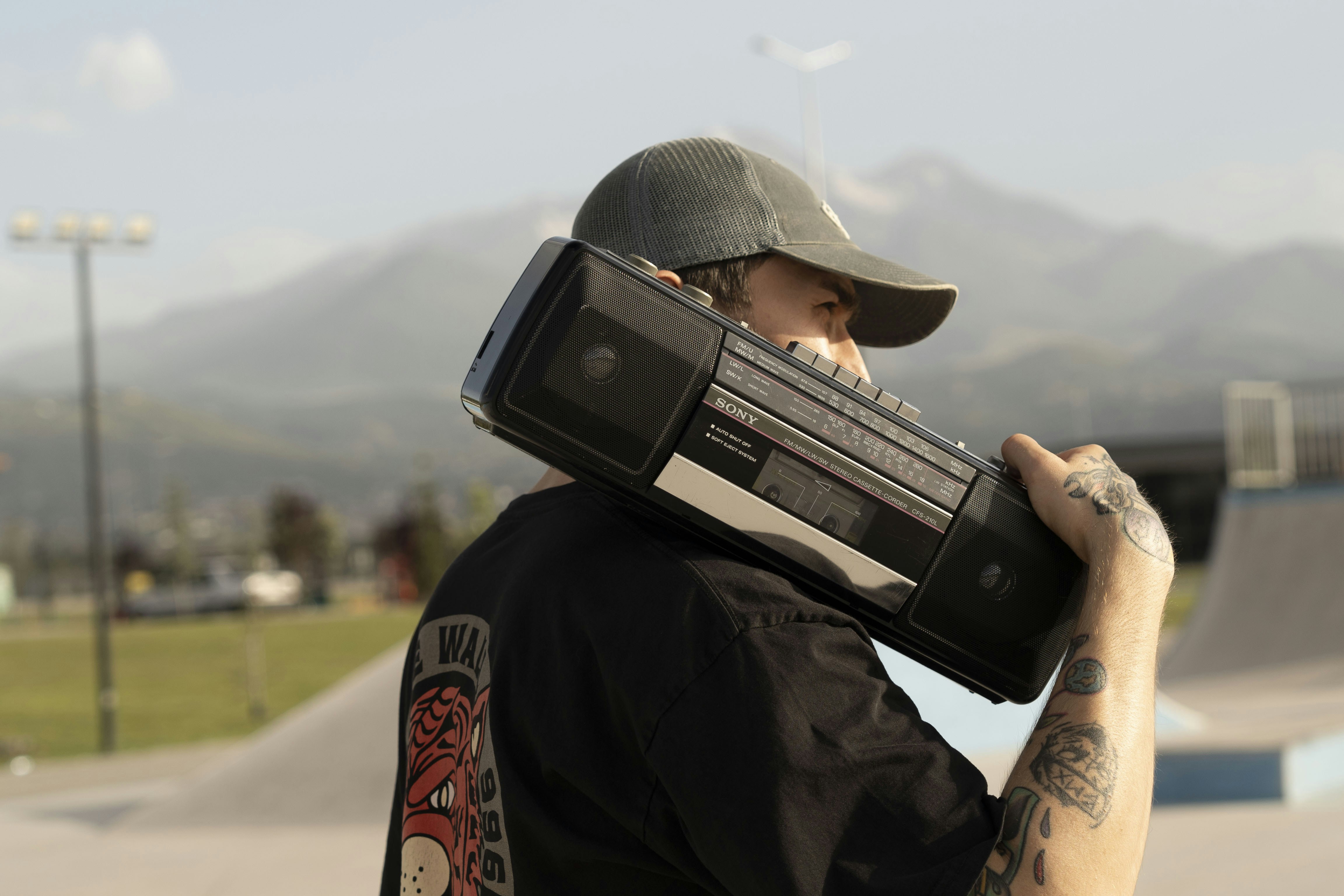 Person carrying a boombox over shoulder with mountains behind