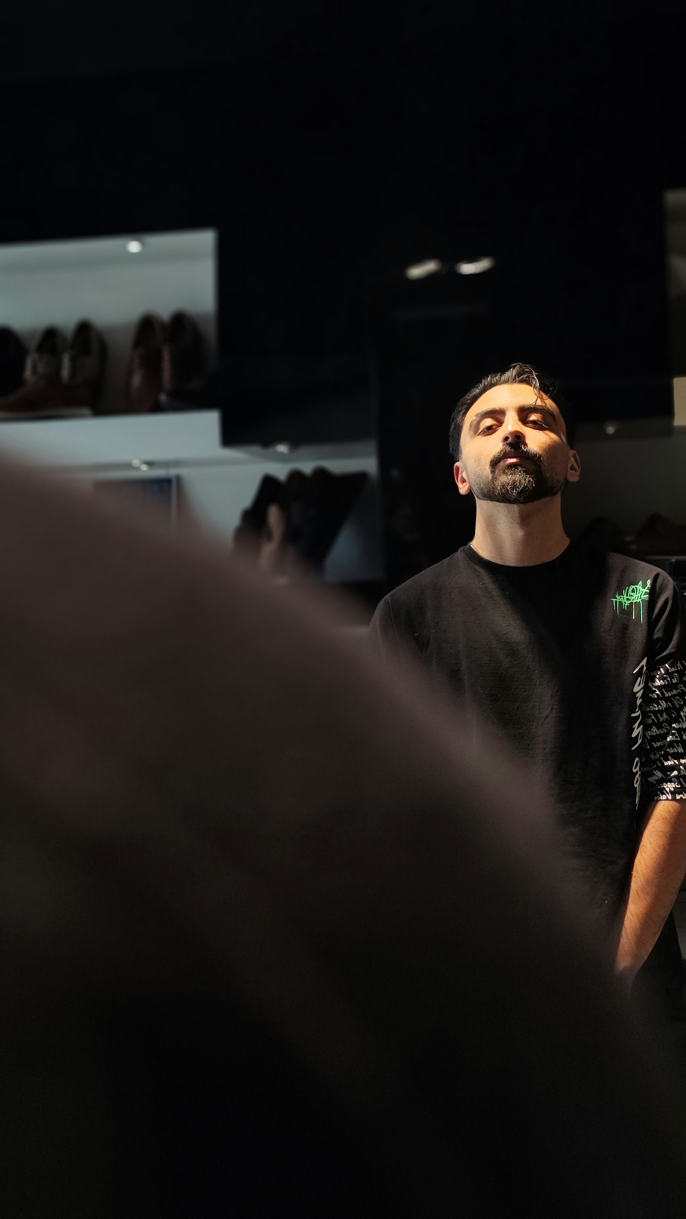 A man in the mirror | Man in black t-shirt with head tilted back.