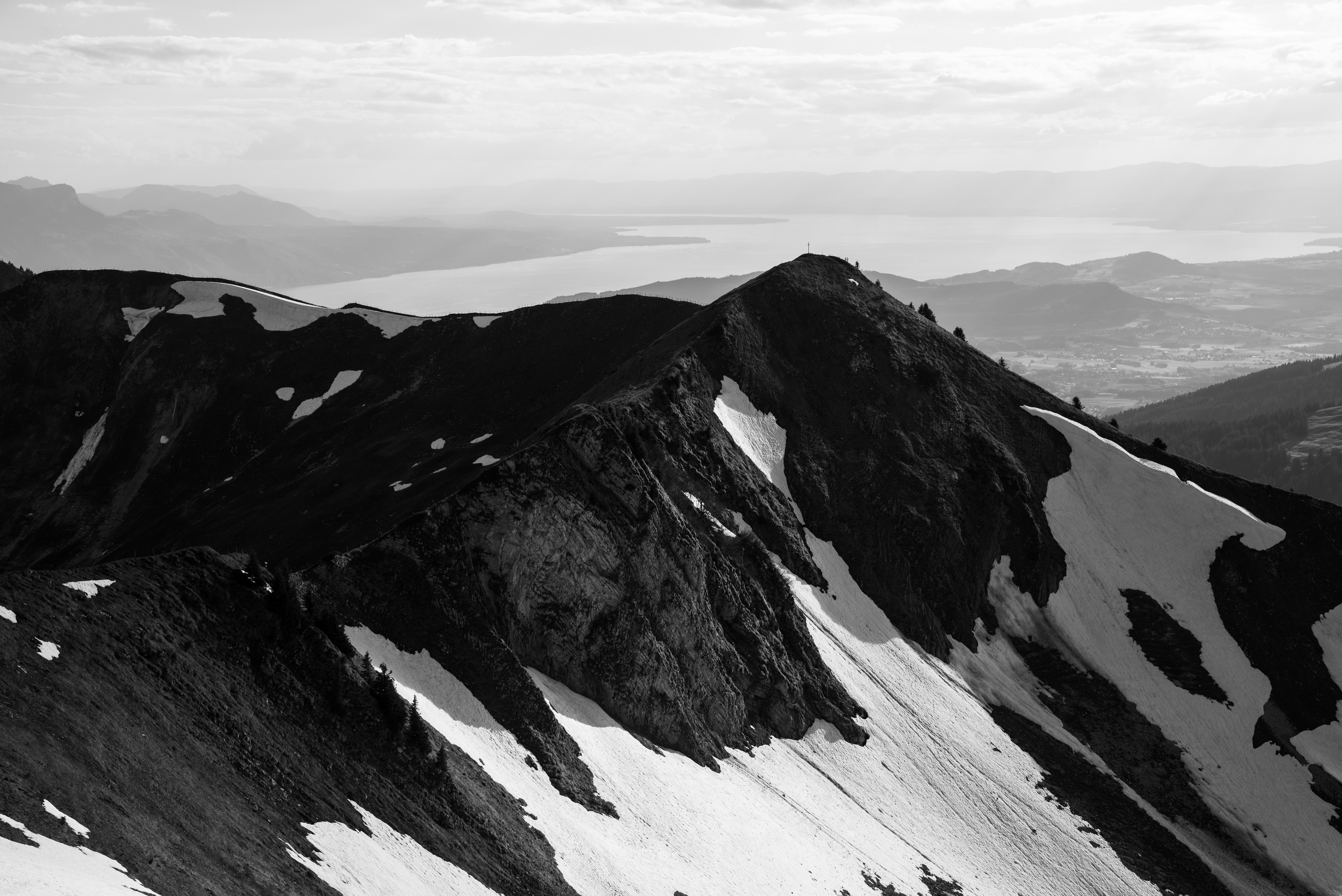 Snow-covered mountain ridge with distant lake view