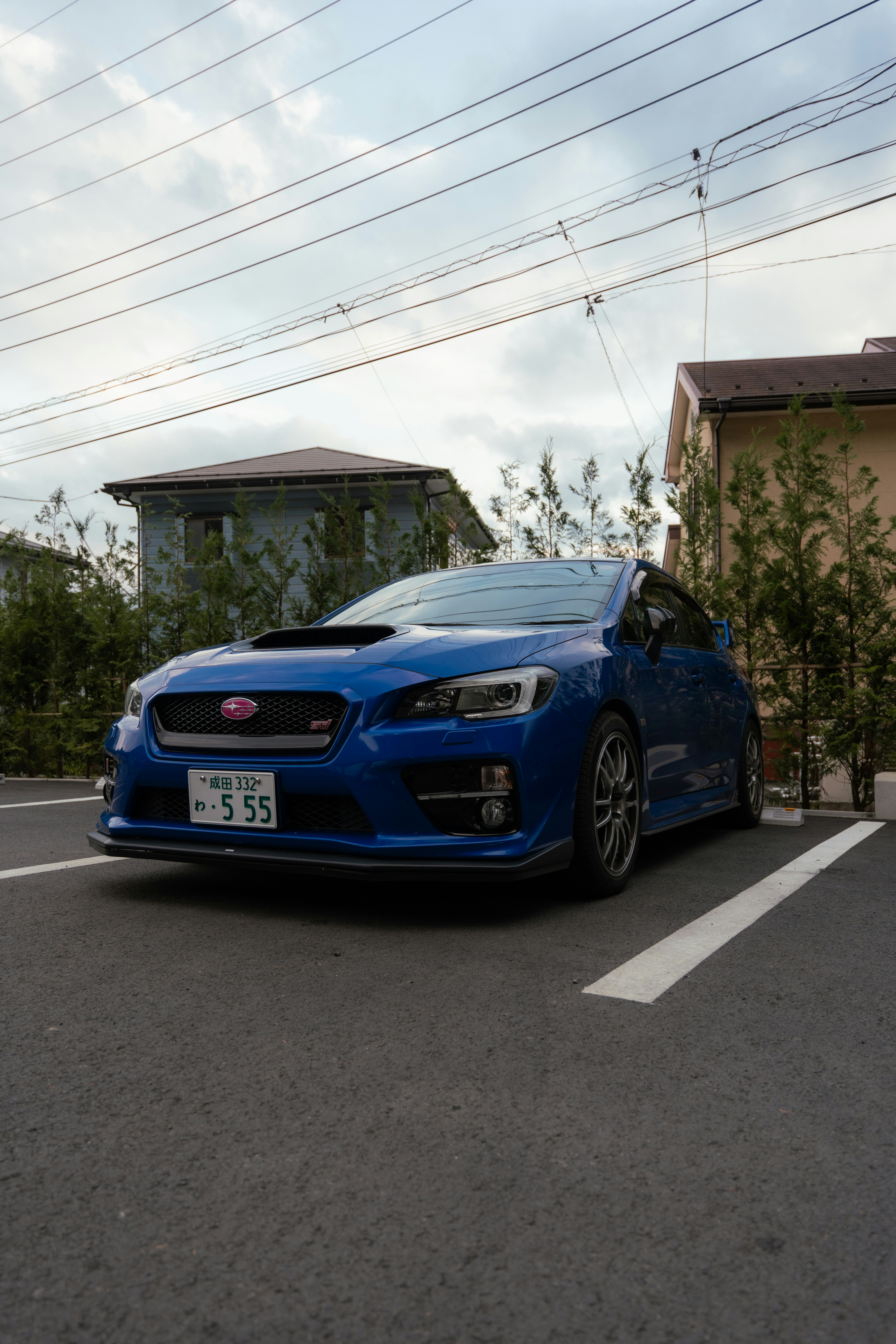 Blue Subaru WRX parked on a city street, showcasing its sporty design against a backdrop of residential buildings.