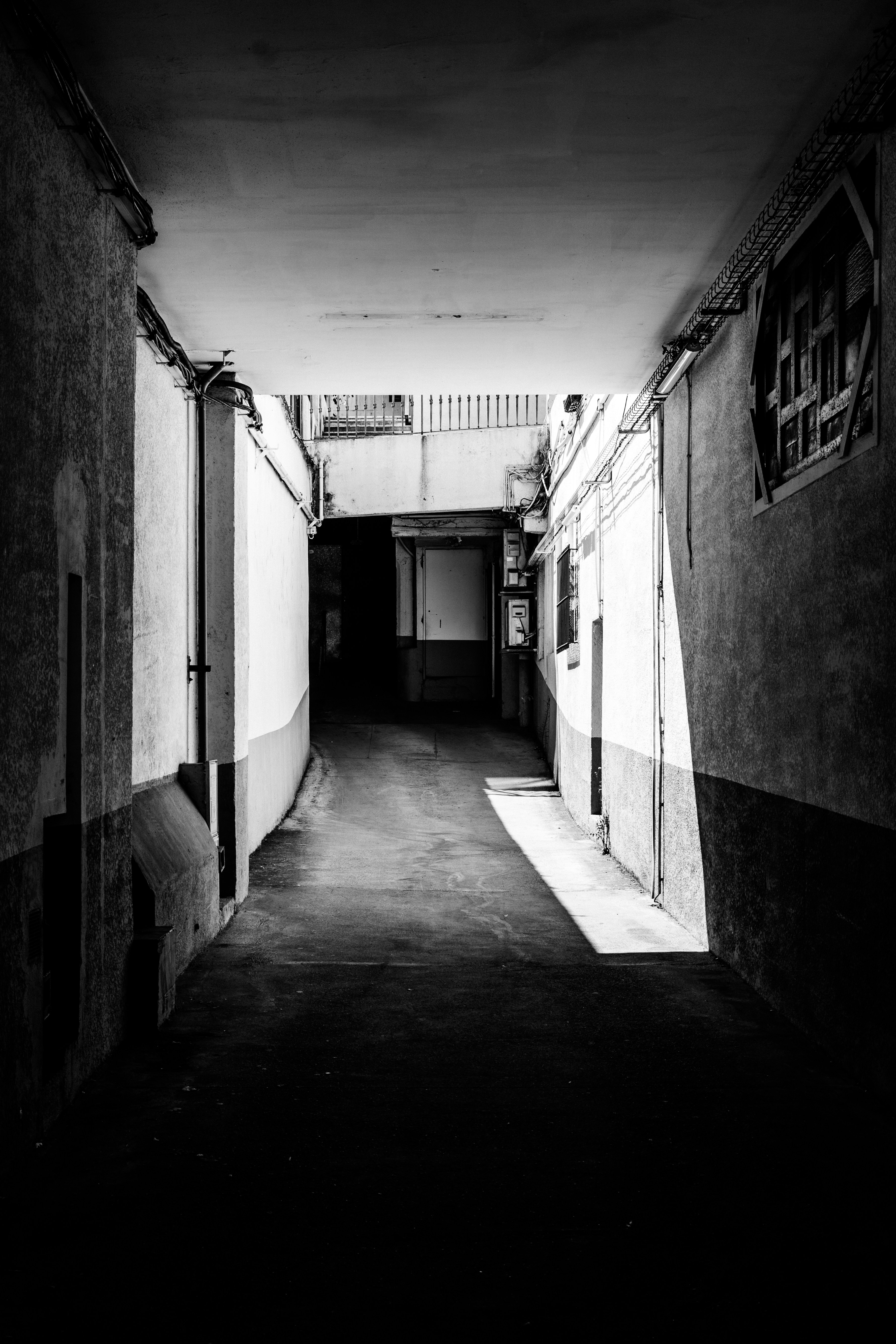 A dark narrow alleyway with dramatic light and shadow.