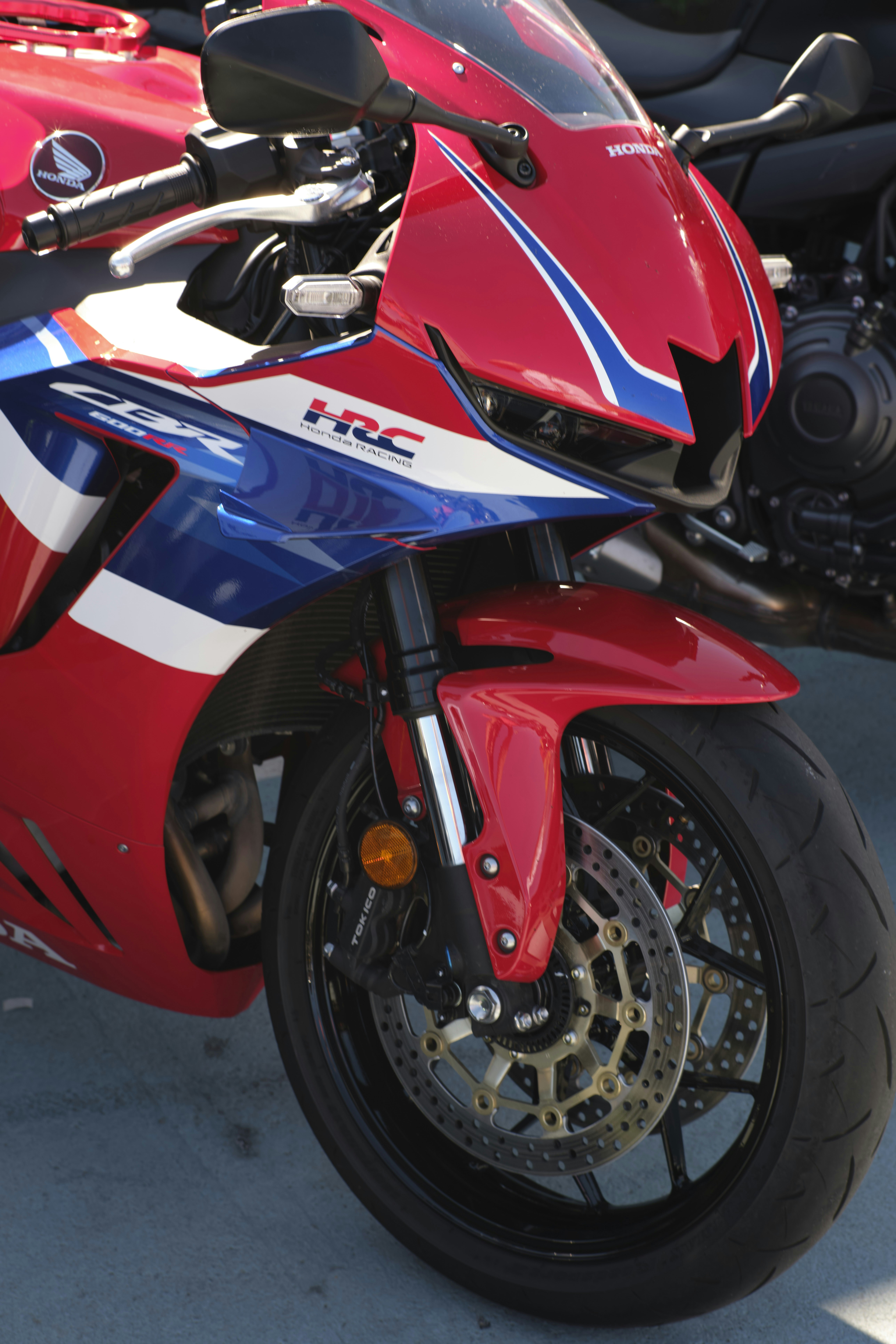 Close-up of a Honda CBR motorcycle showcasing its vibrant red, white, and blue design and intricate brake system.