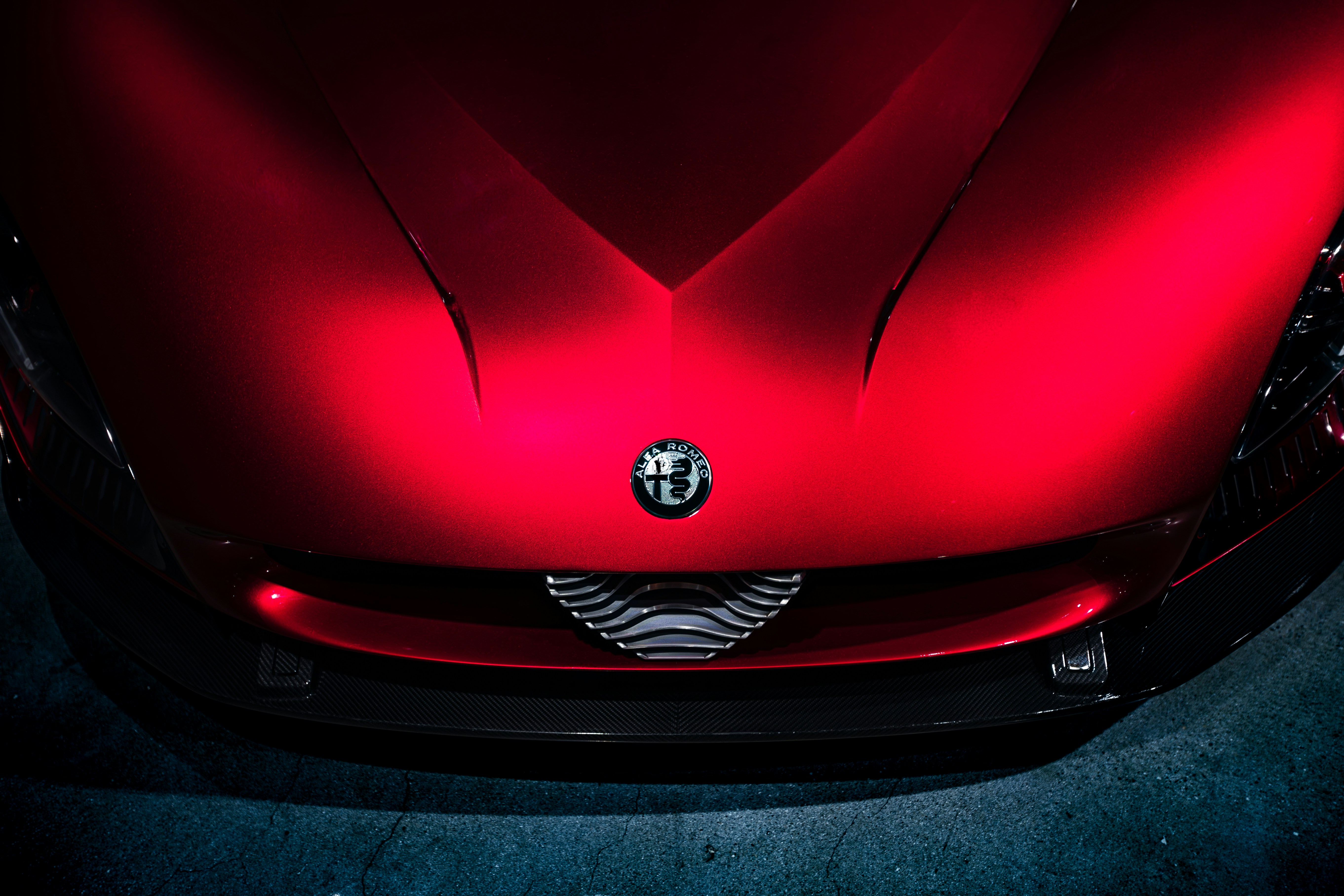 Close-up of a shiny red car hood with emblem.