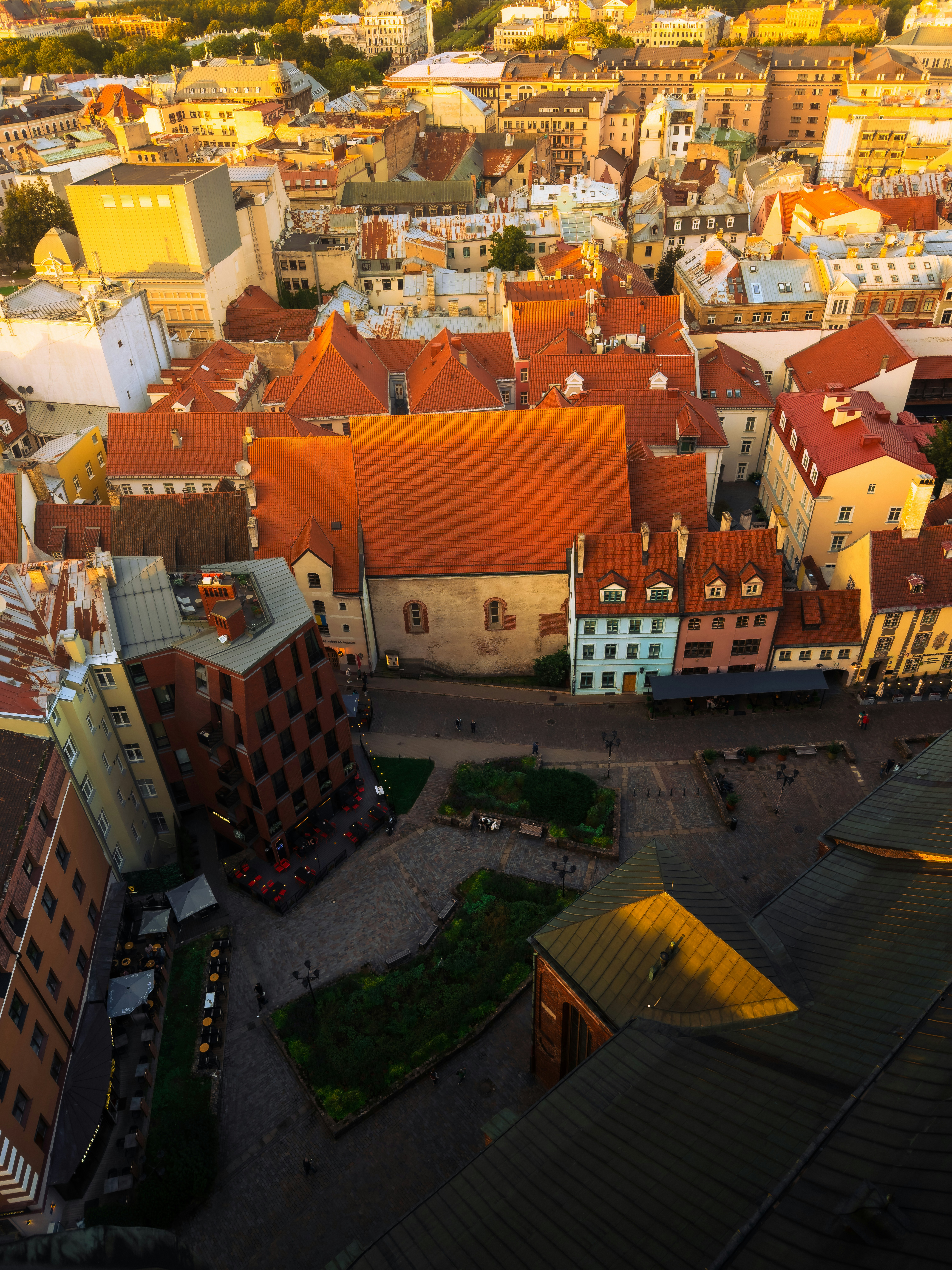 Aerial view of a vibrant cityscape showcasing a mix of colorful rooftops and winding streets, with people strolling below.