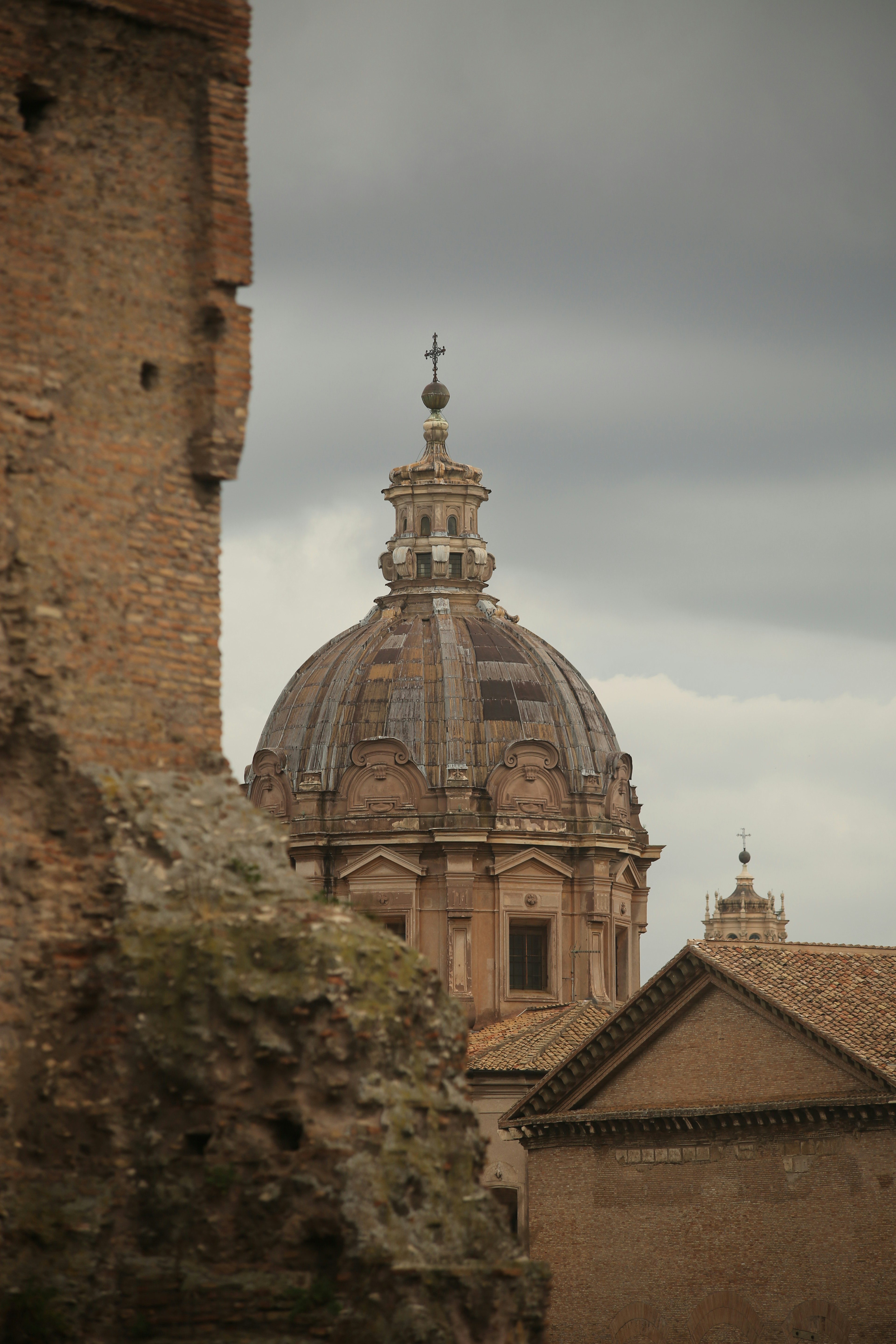 A view from the remains of the colosseum towards the city featuring a dome. Image taken 2025. | Ancient roman dome with cloudy sky