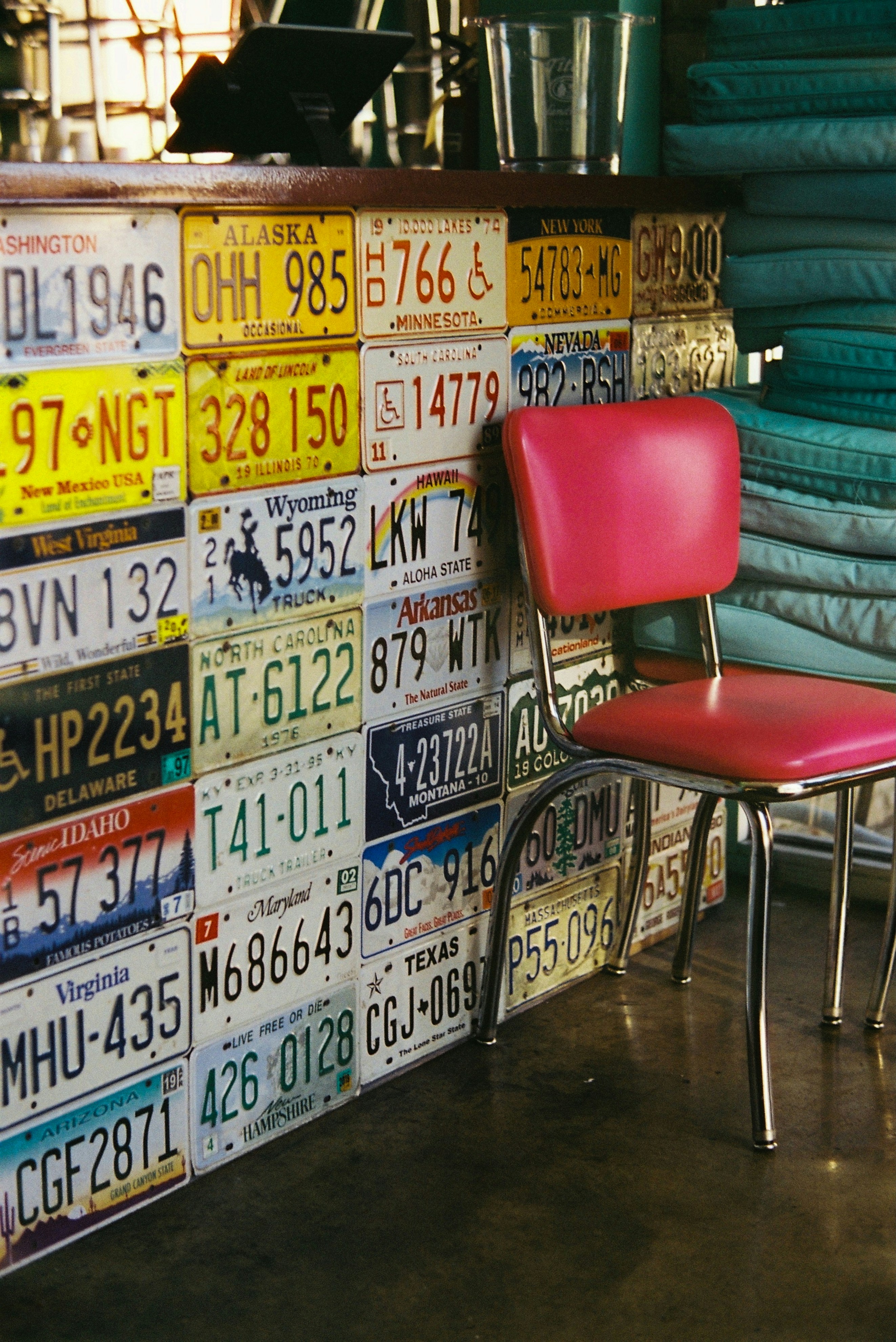 Wall decorated with colorful license plates and pink chair photo – Free ...