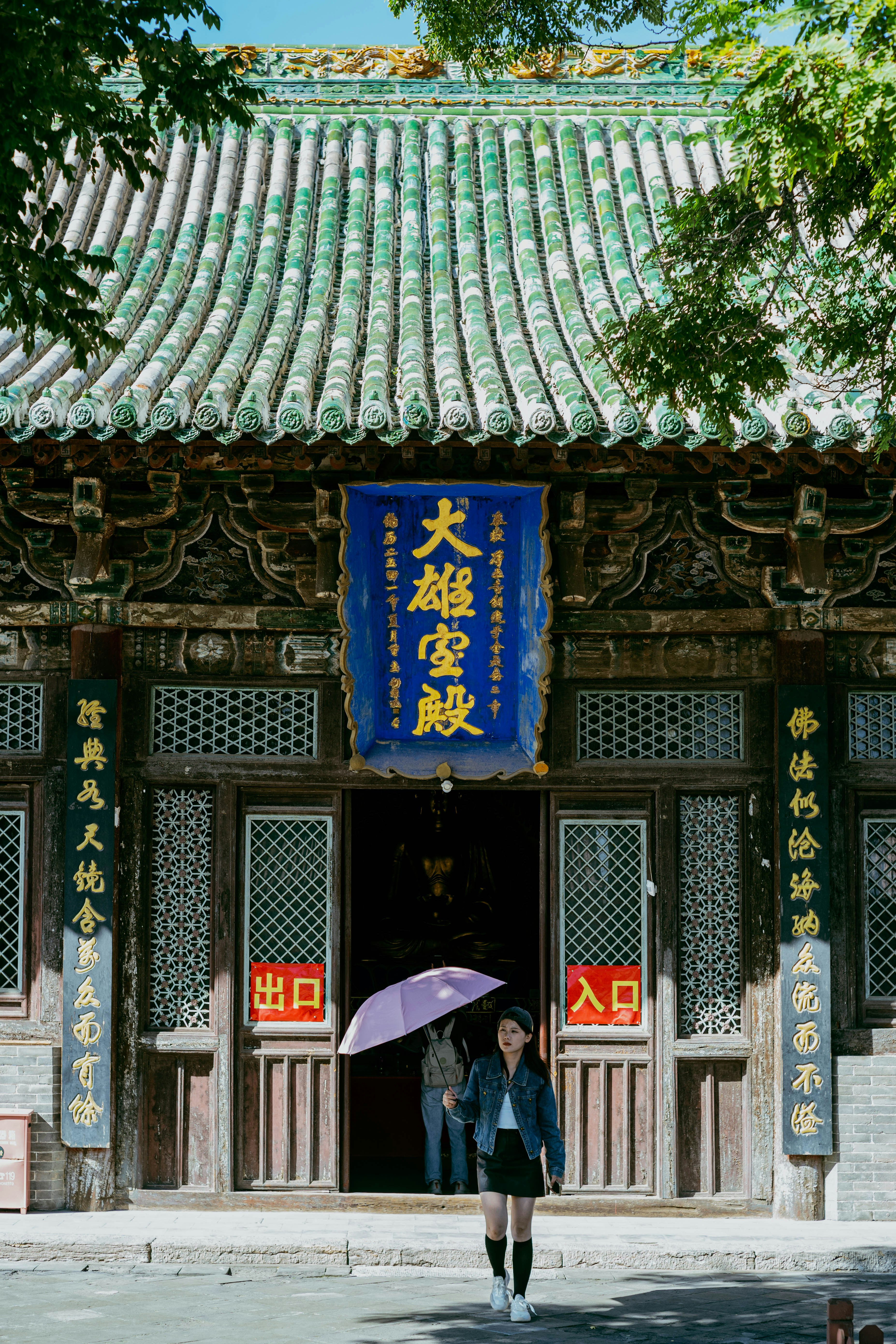 Woman with umbrella enters traditional temple building
