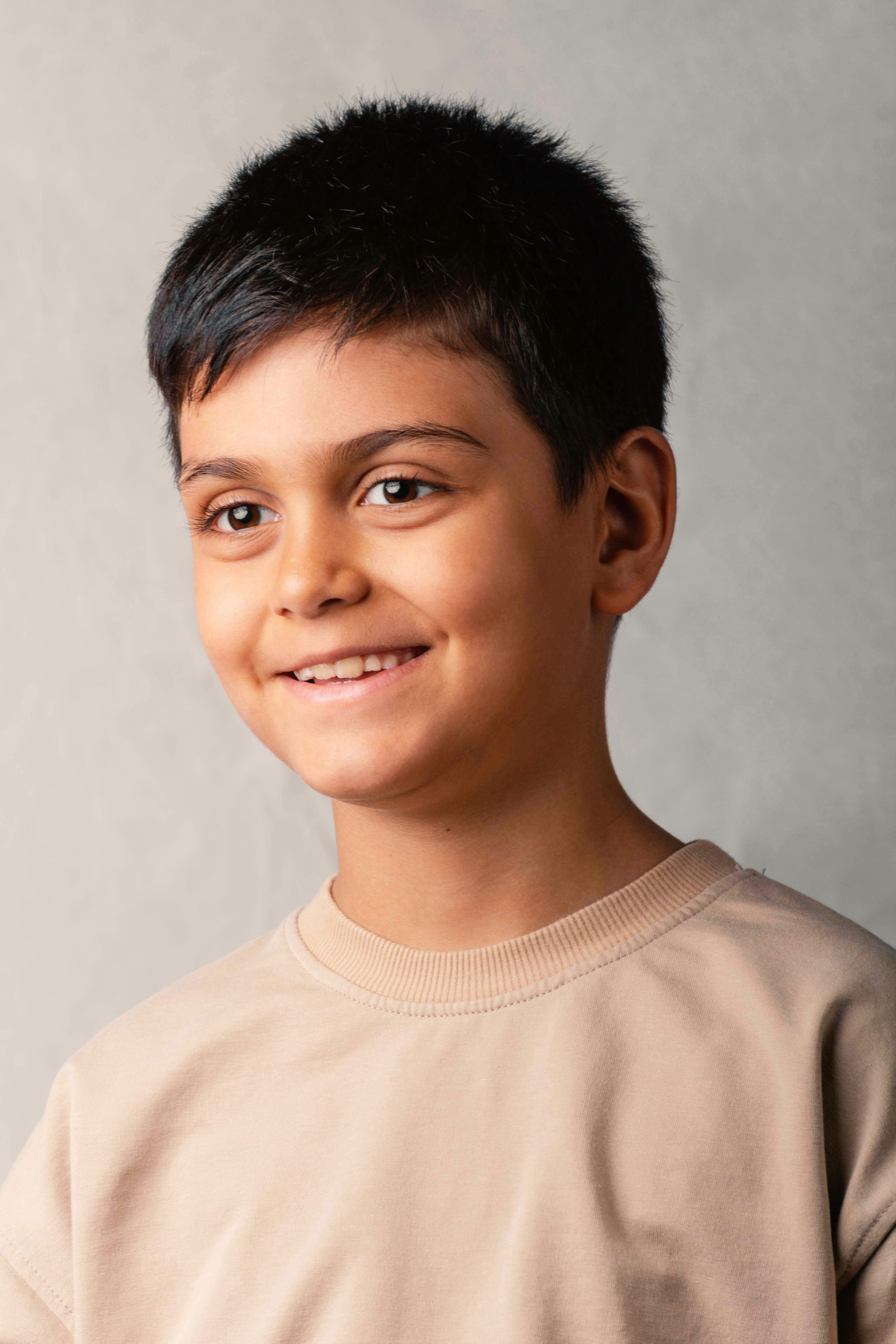 A young boy with dark hair smiles warmly.